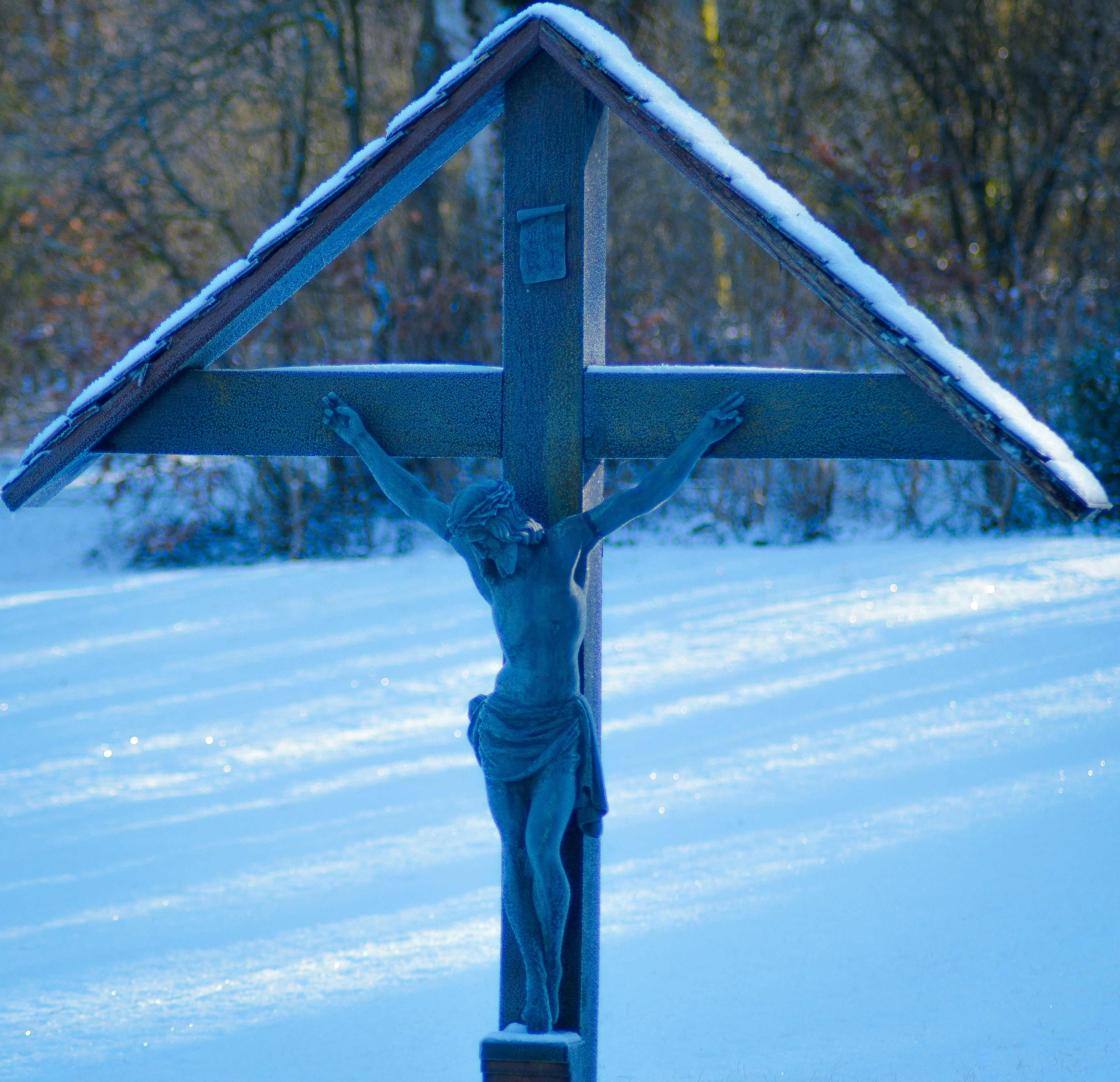 Azure hush: a snow-dusted crucifix under winter light