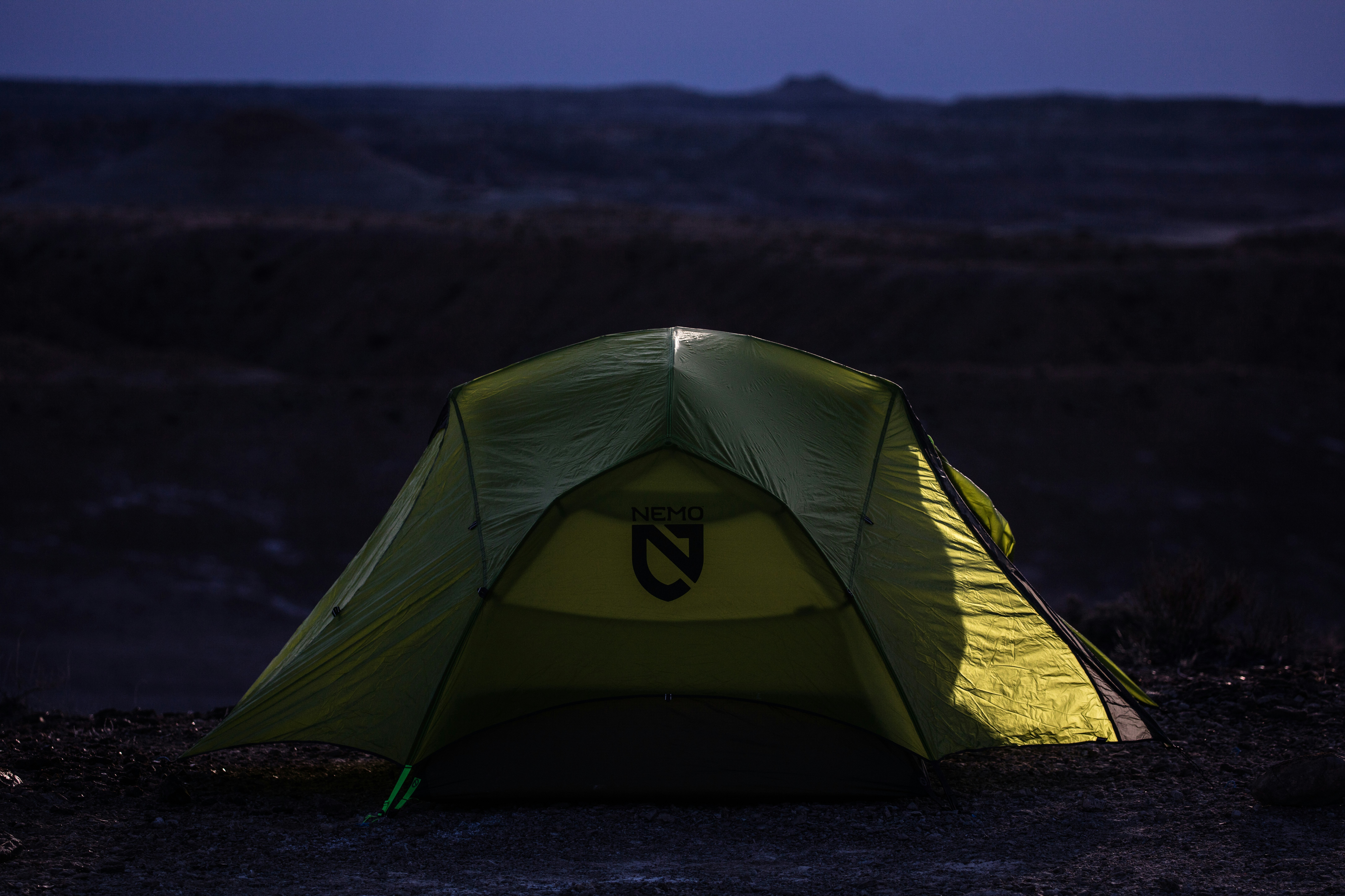 Lone Neon Tent Shrouded by Night over a Quiet Distant Plain
