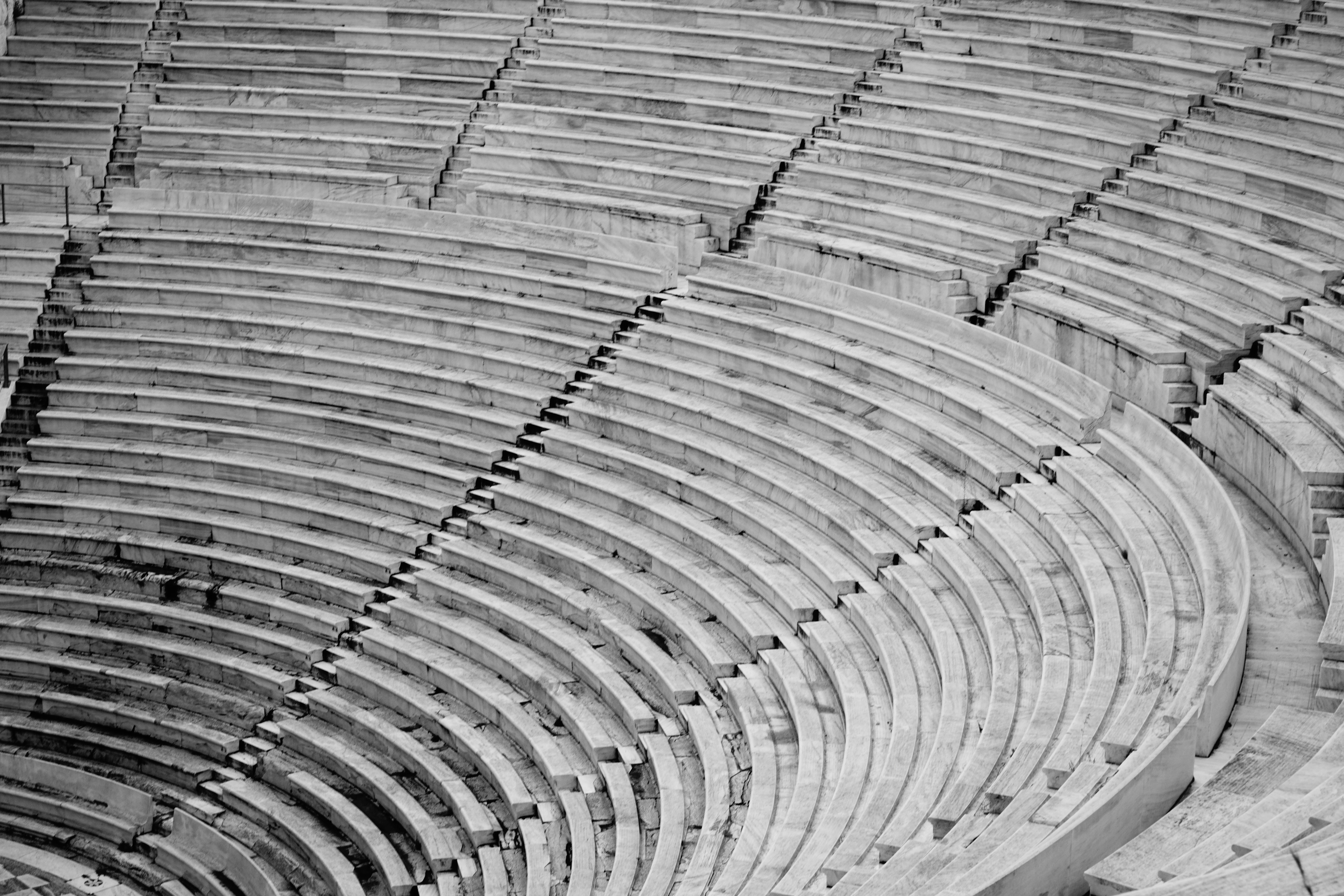 Curved stone seating of an ancient amphitheater in grayscale, highlighting architectural precision.