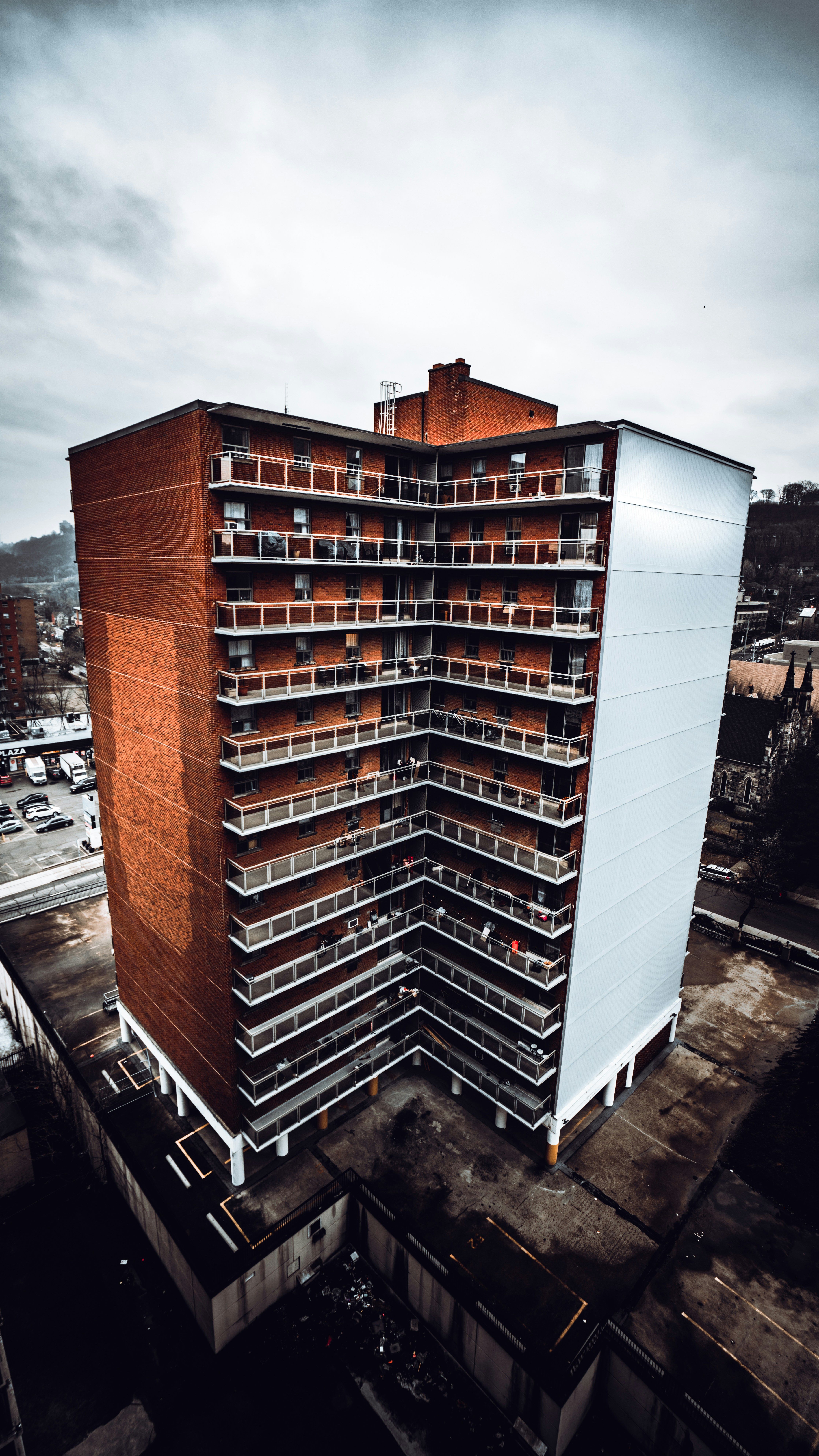 A modern residential building with a striking geometric design, showcasing a mix of brick and smooth white surfaces against a cloudy sky.