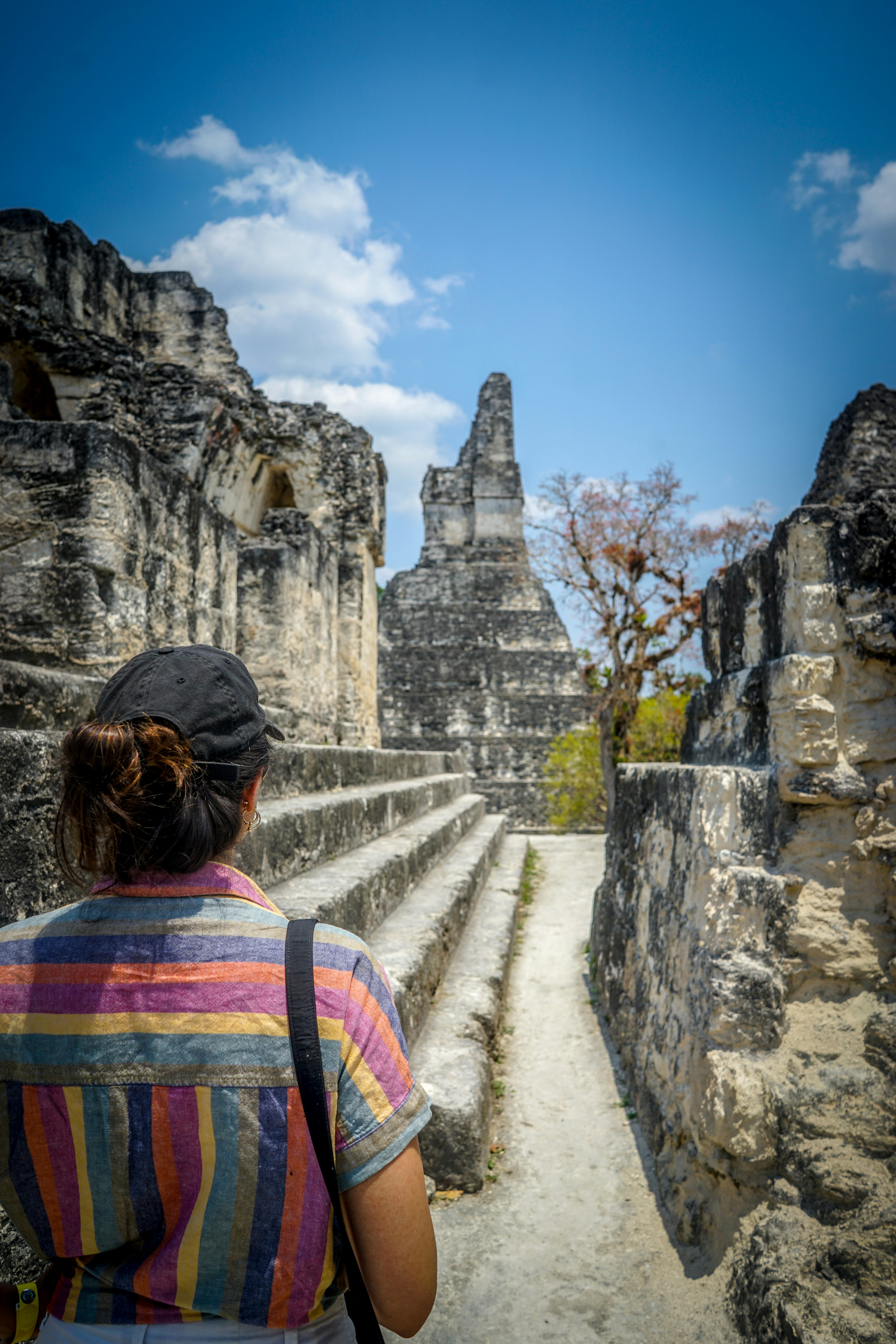 Visitor exploring the ancient ruins of Tikal, surrounded by towering stone structures and vibrant foliage.