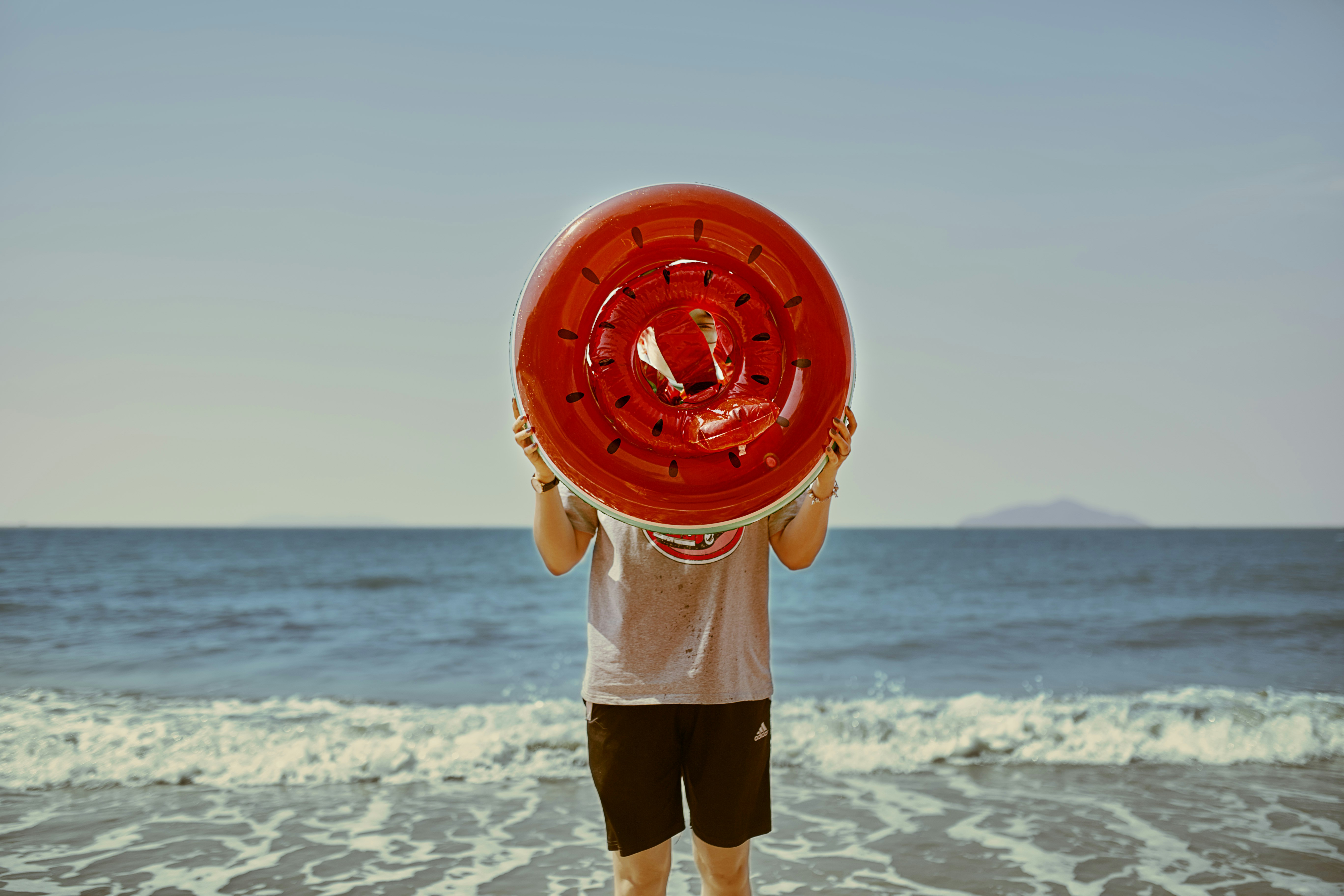 Red Lifebuoy at the Shore: A Centered Beach Portrait of Summer Play