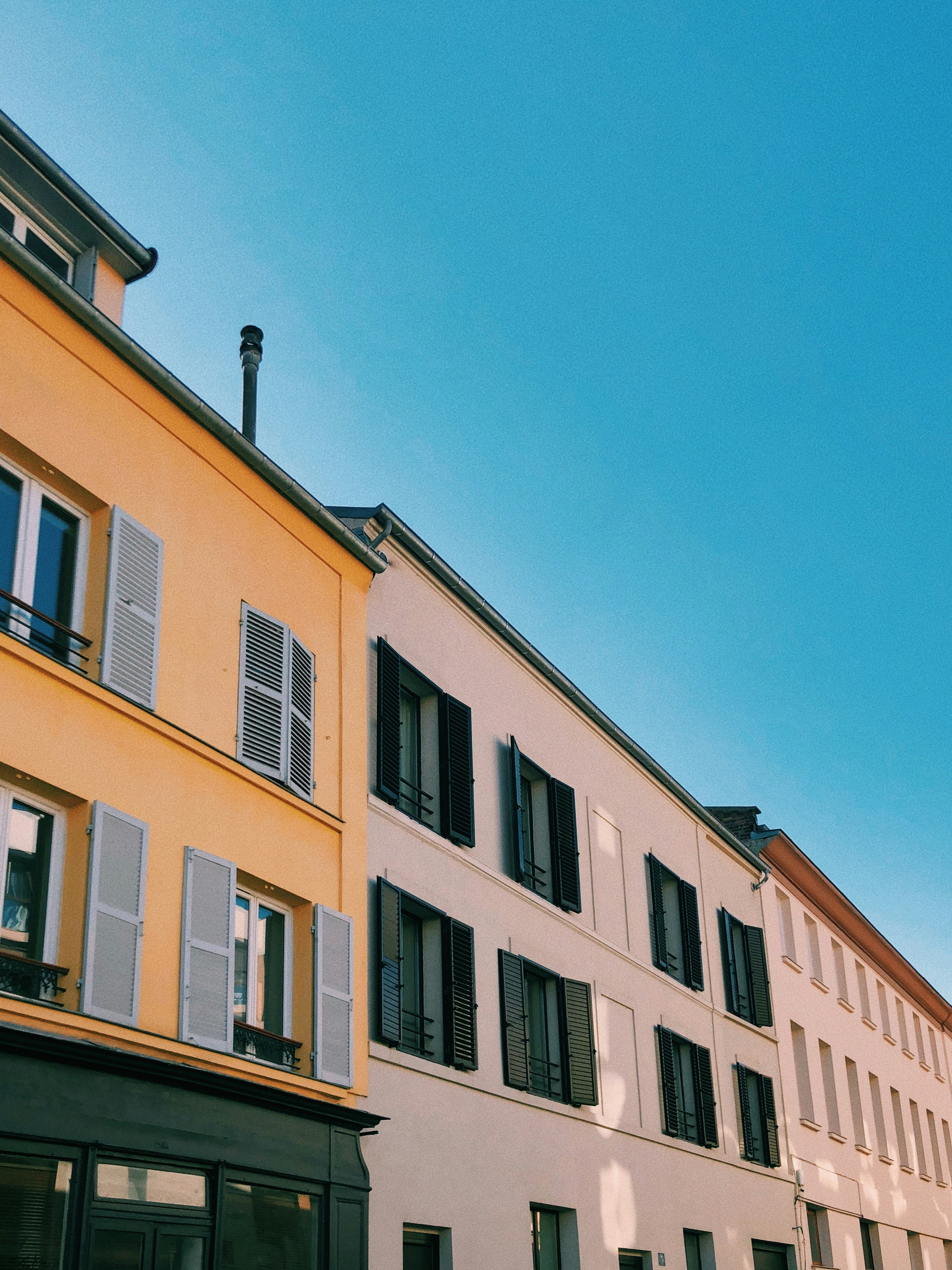 Colorful buildings with shuttered windows against a clear blue sky.