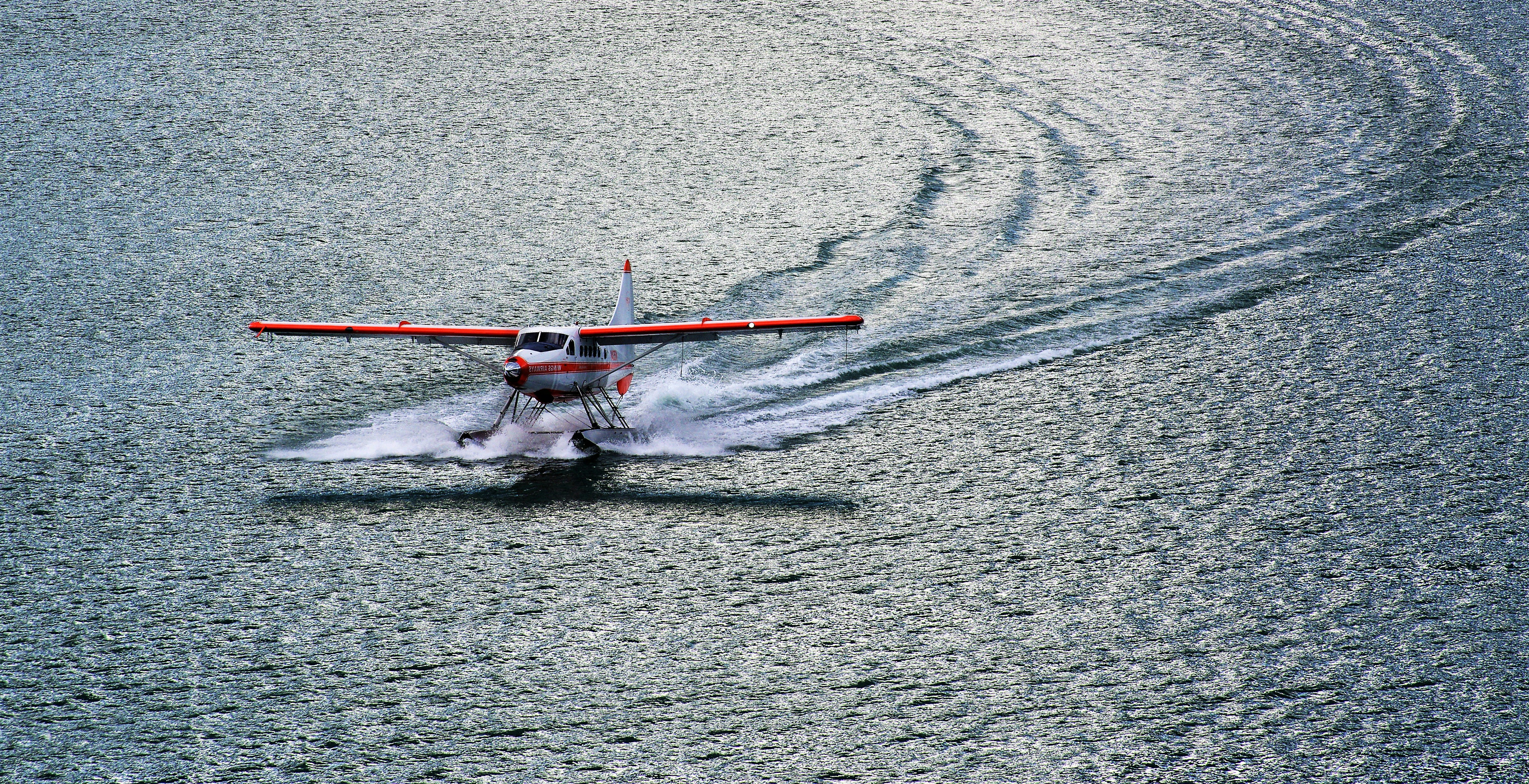 Red floatplane tracing a living wake over a glassy lakescape