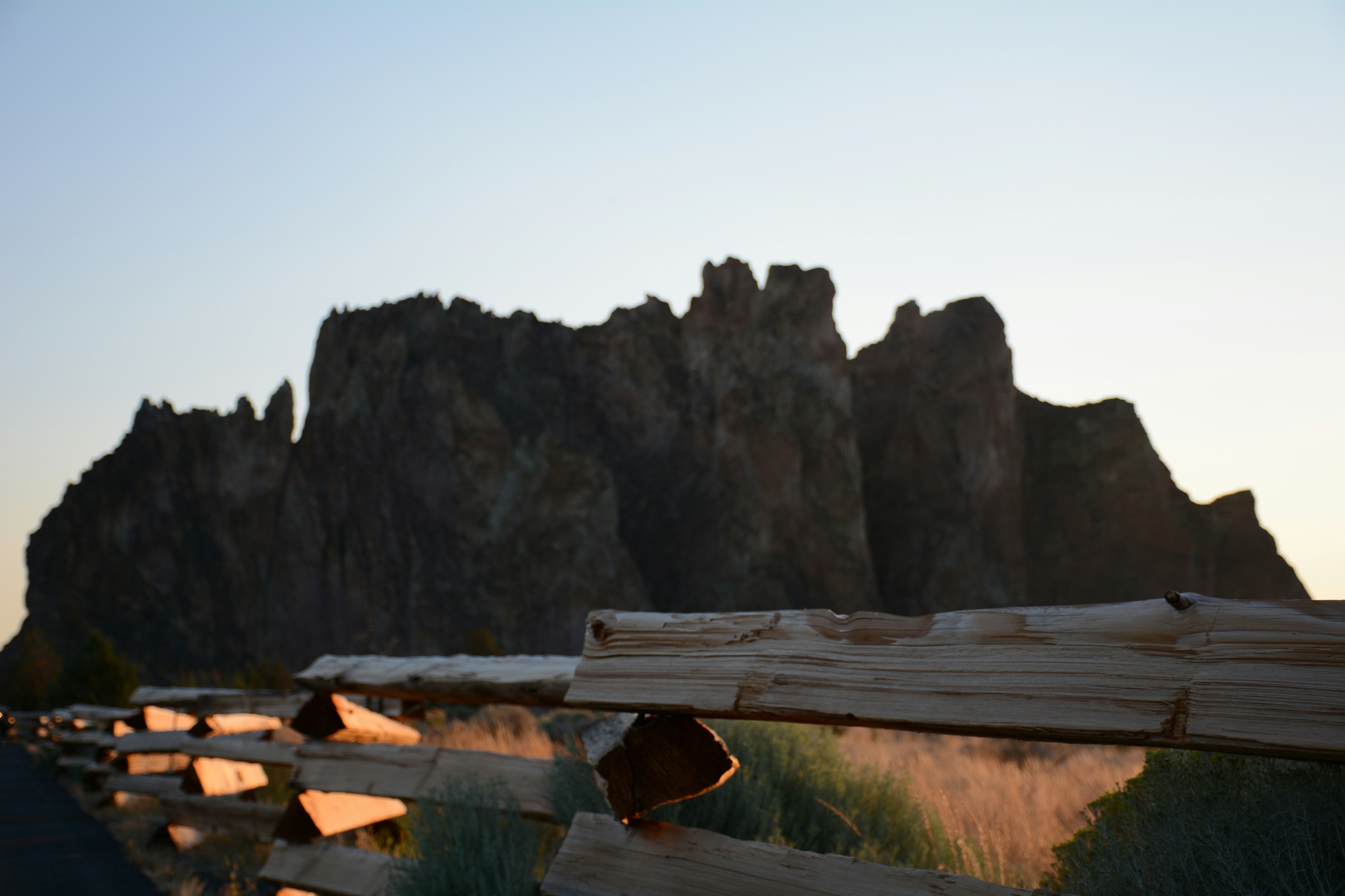Sun-worn fence leads the eye toward rugged cliffs at golden hour