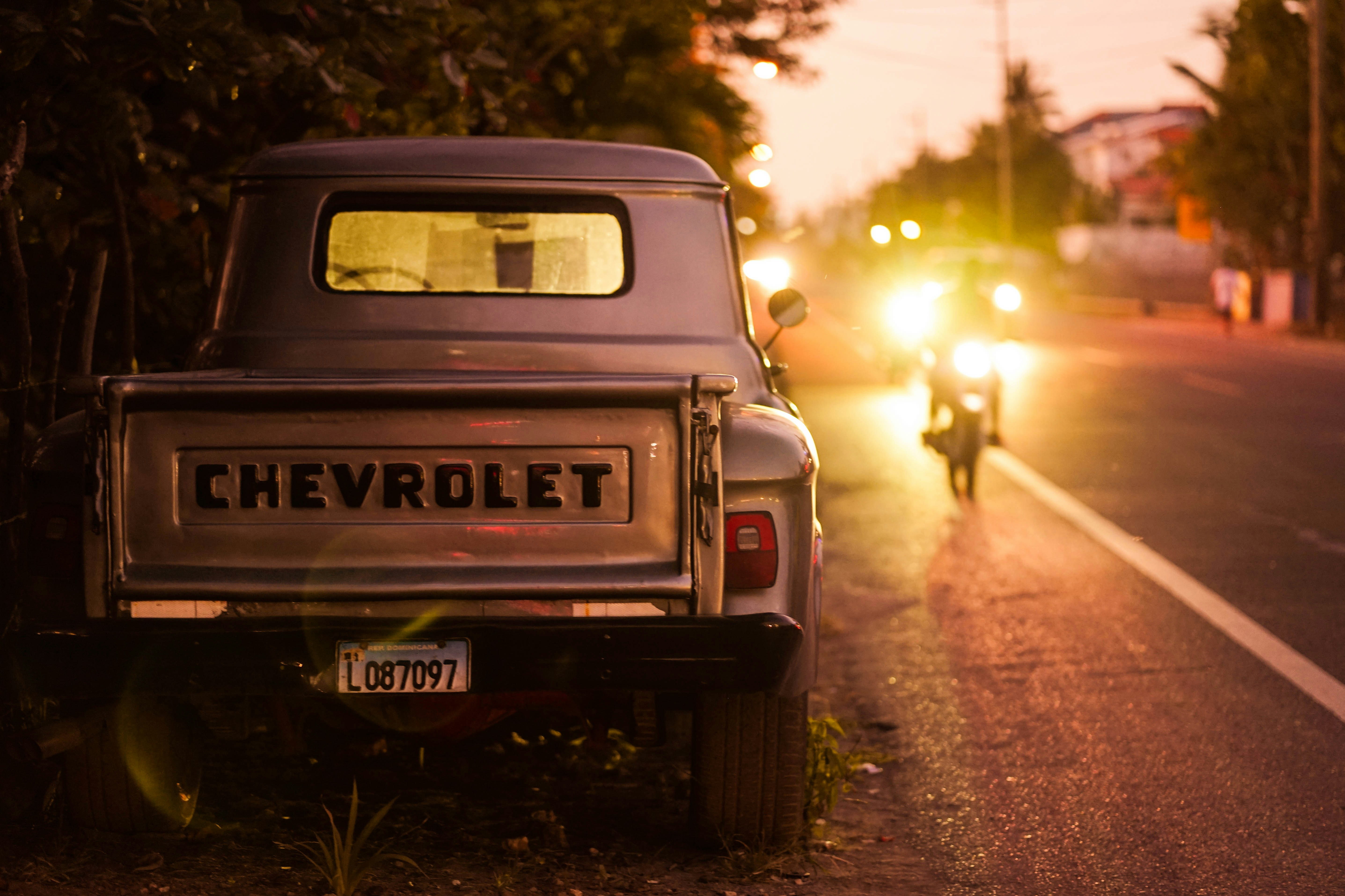 Amber Hour on the Shoulder: Vintage Chevy and a Distant Headlight