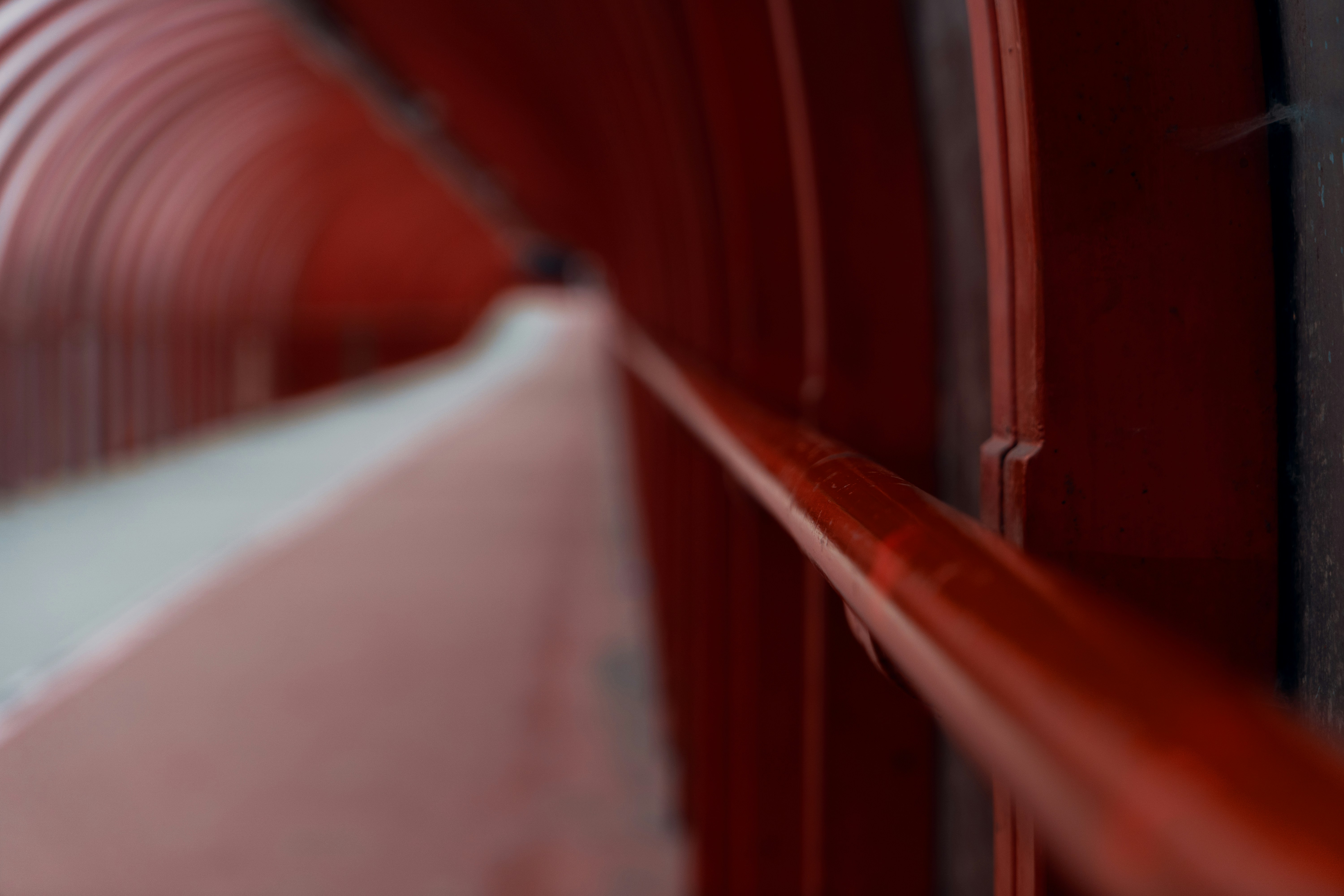 Blurred view of a curved red tunnel with a focus on the handrail.