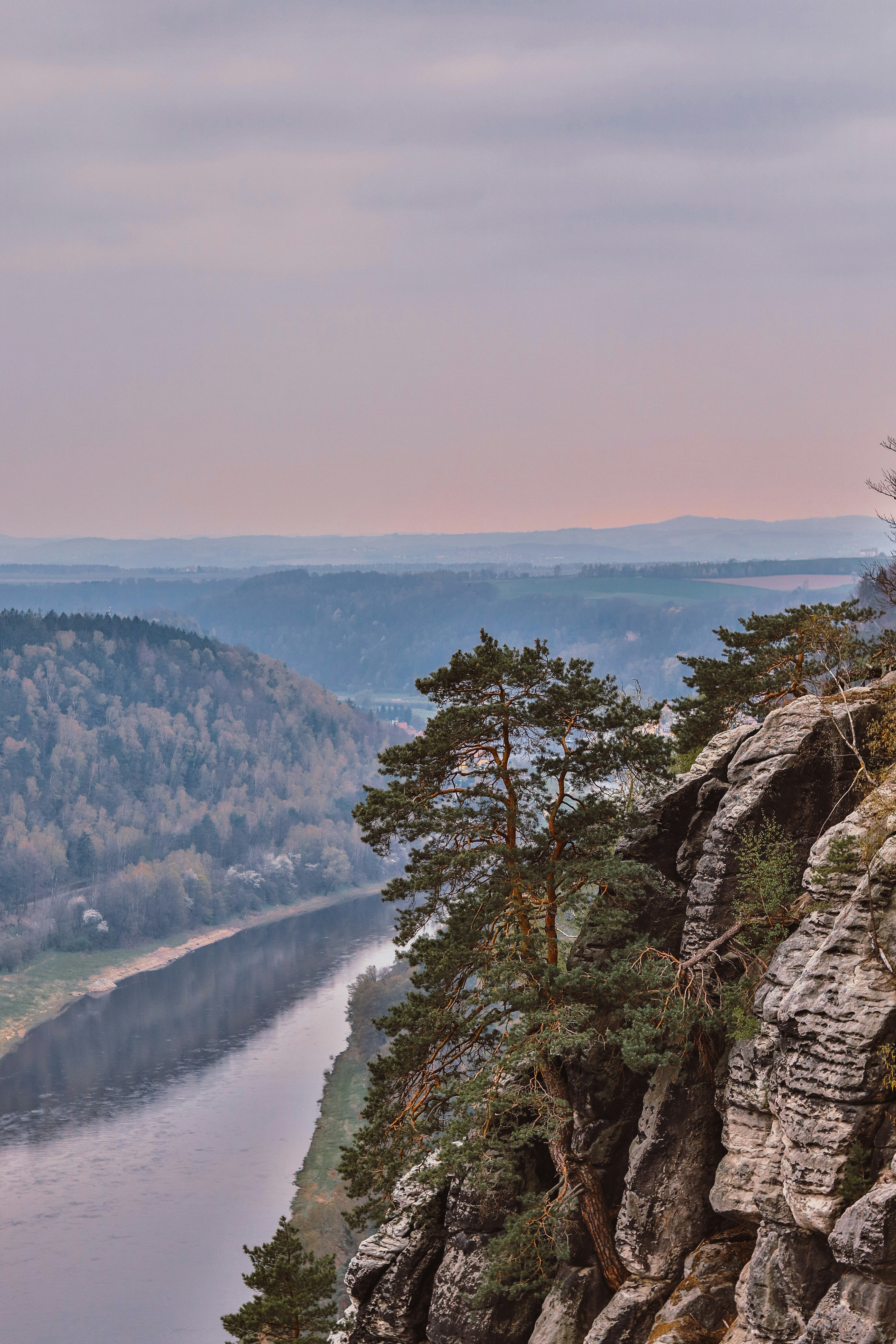 A person standing on a cliff overlooking a river photo – Free Grey ...