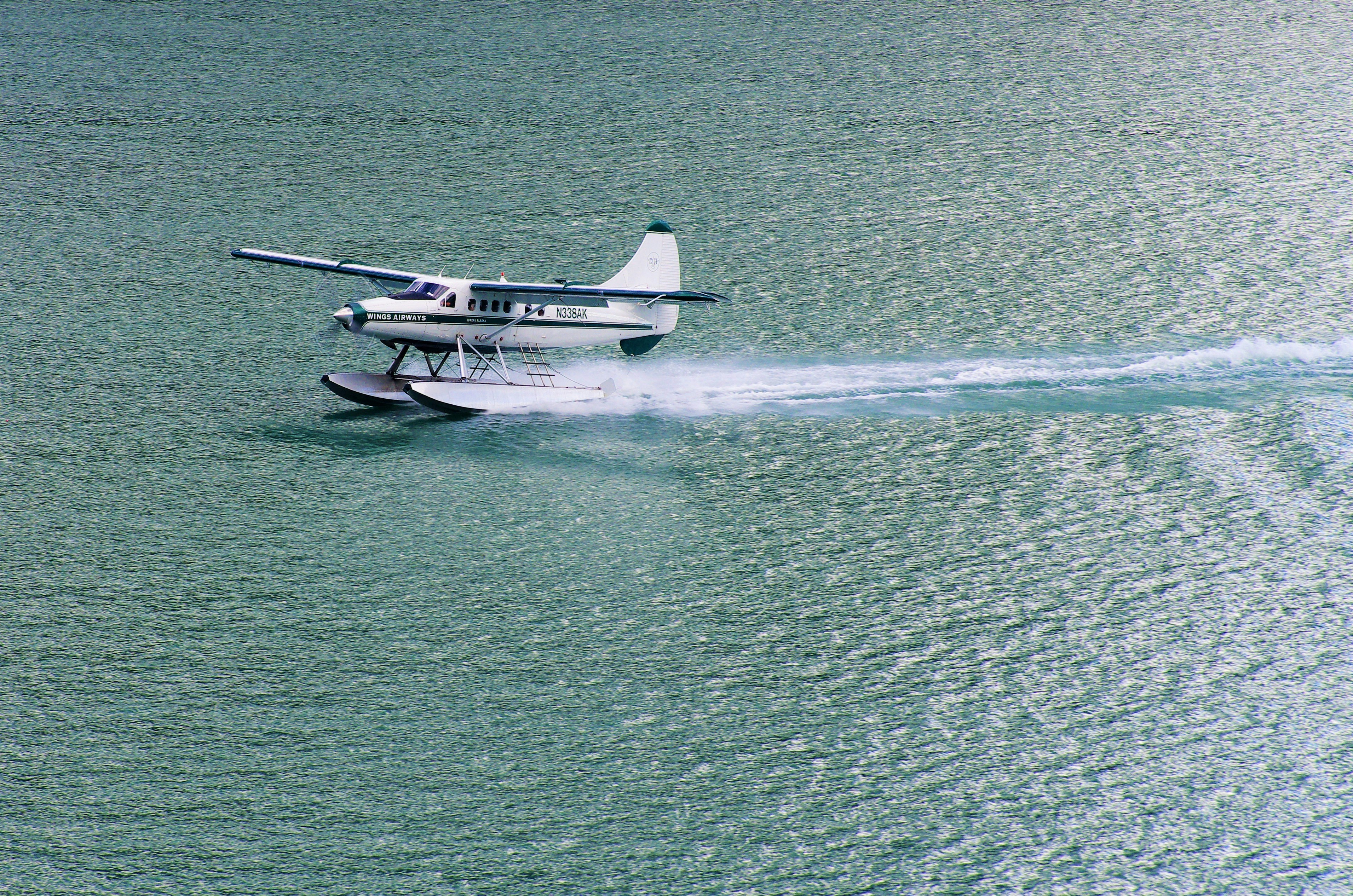 Seaplane skimming across tranquil waters, leaving a gentle wake behind. The serene environment enhances the aircraft's elegance.