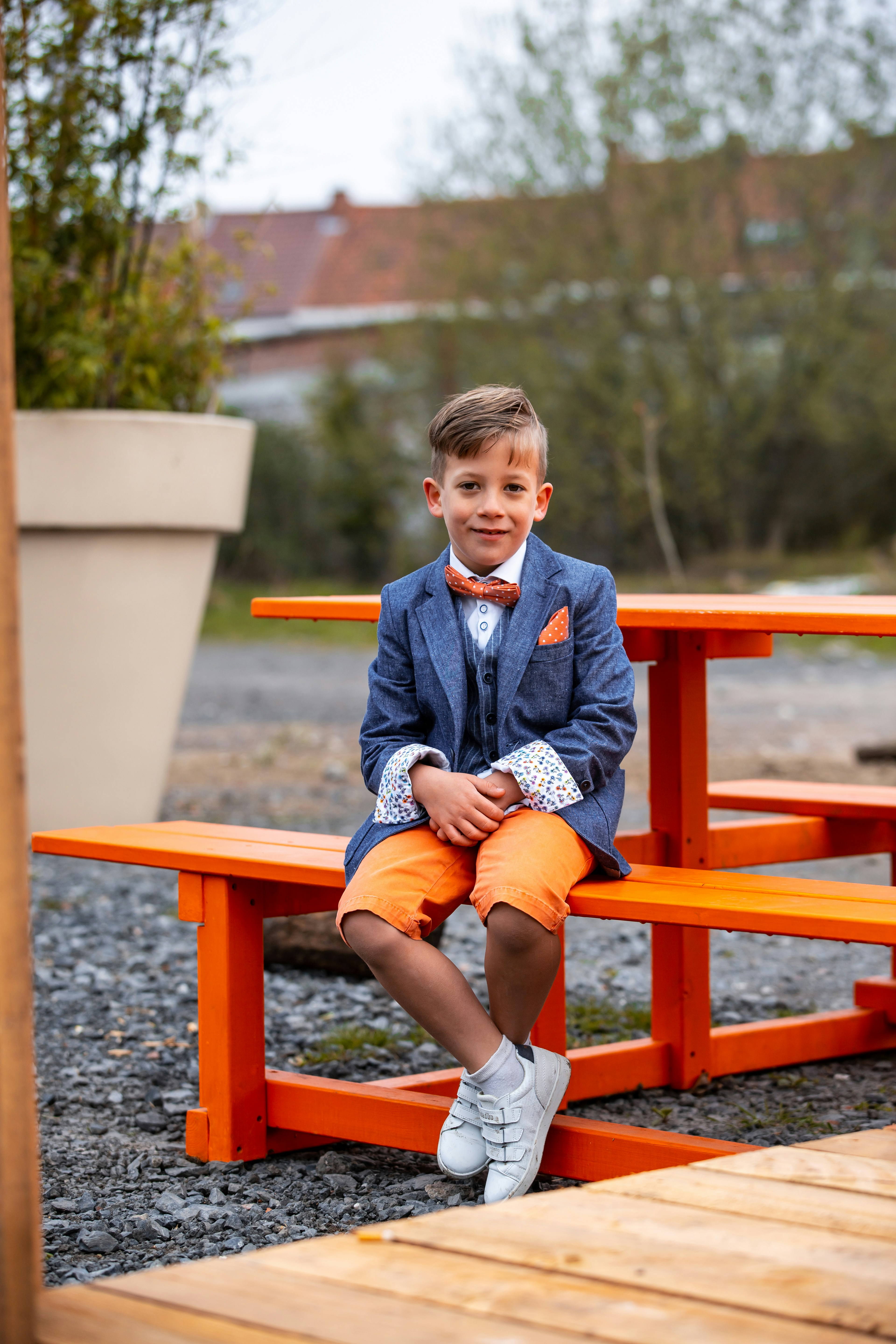 Dapper boy on an orange bench beneath a soft autumn glow