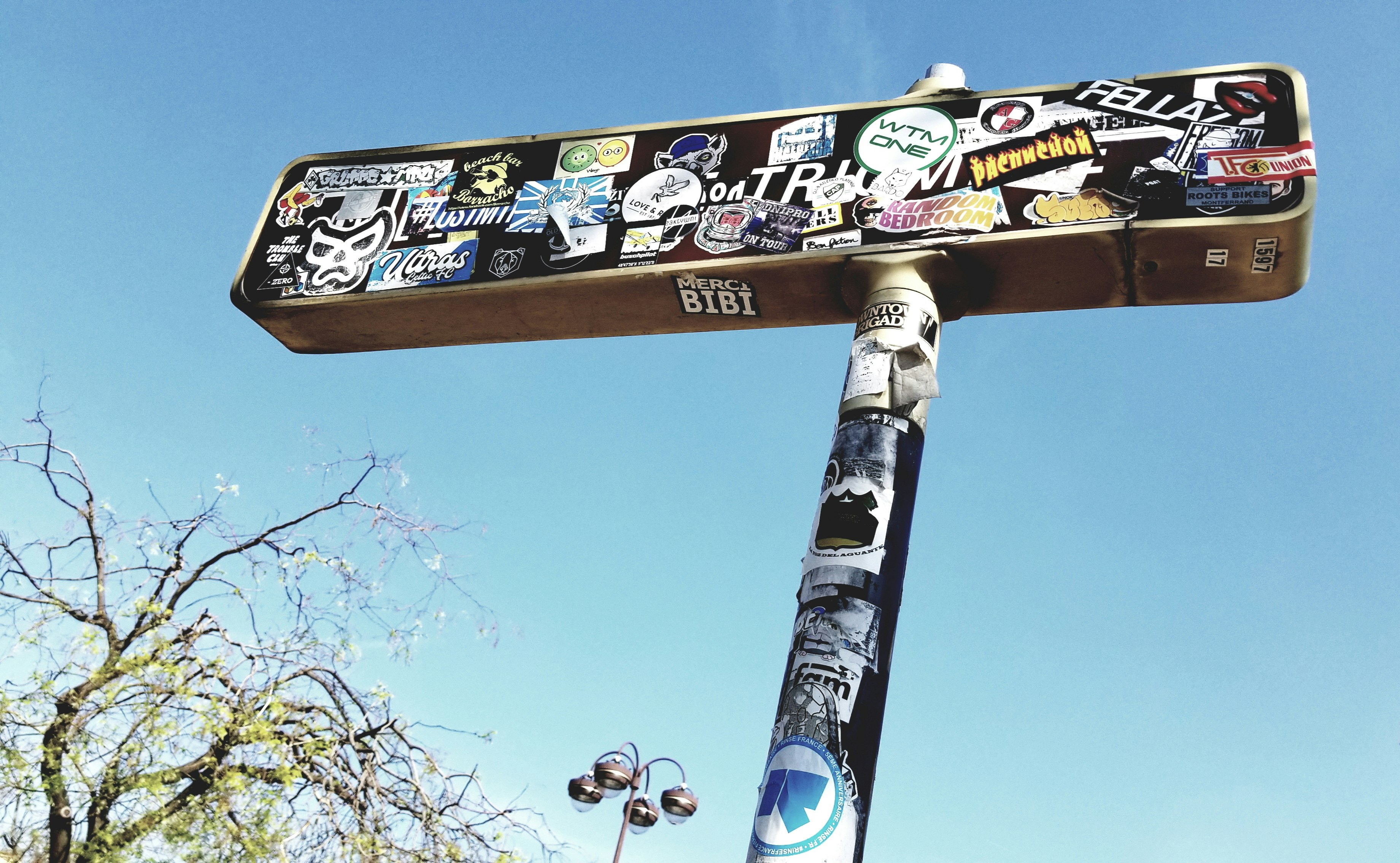 Stickered Signpost Reaching Toward a Clear Blue Sky