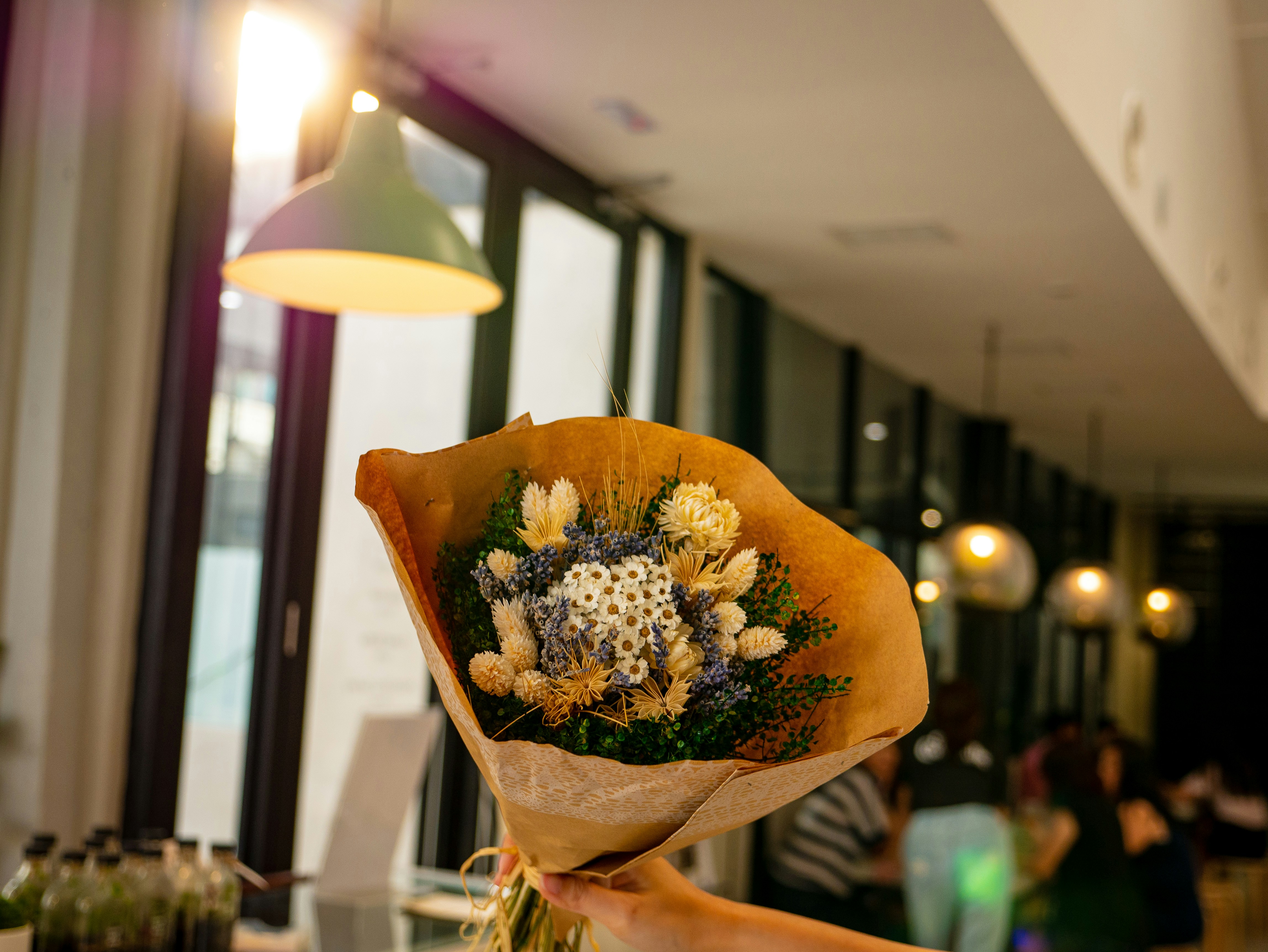 Petals in Focus: A Wrapped Bouquet Backlit by Warm Cafe Light