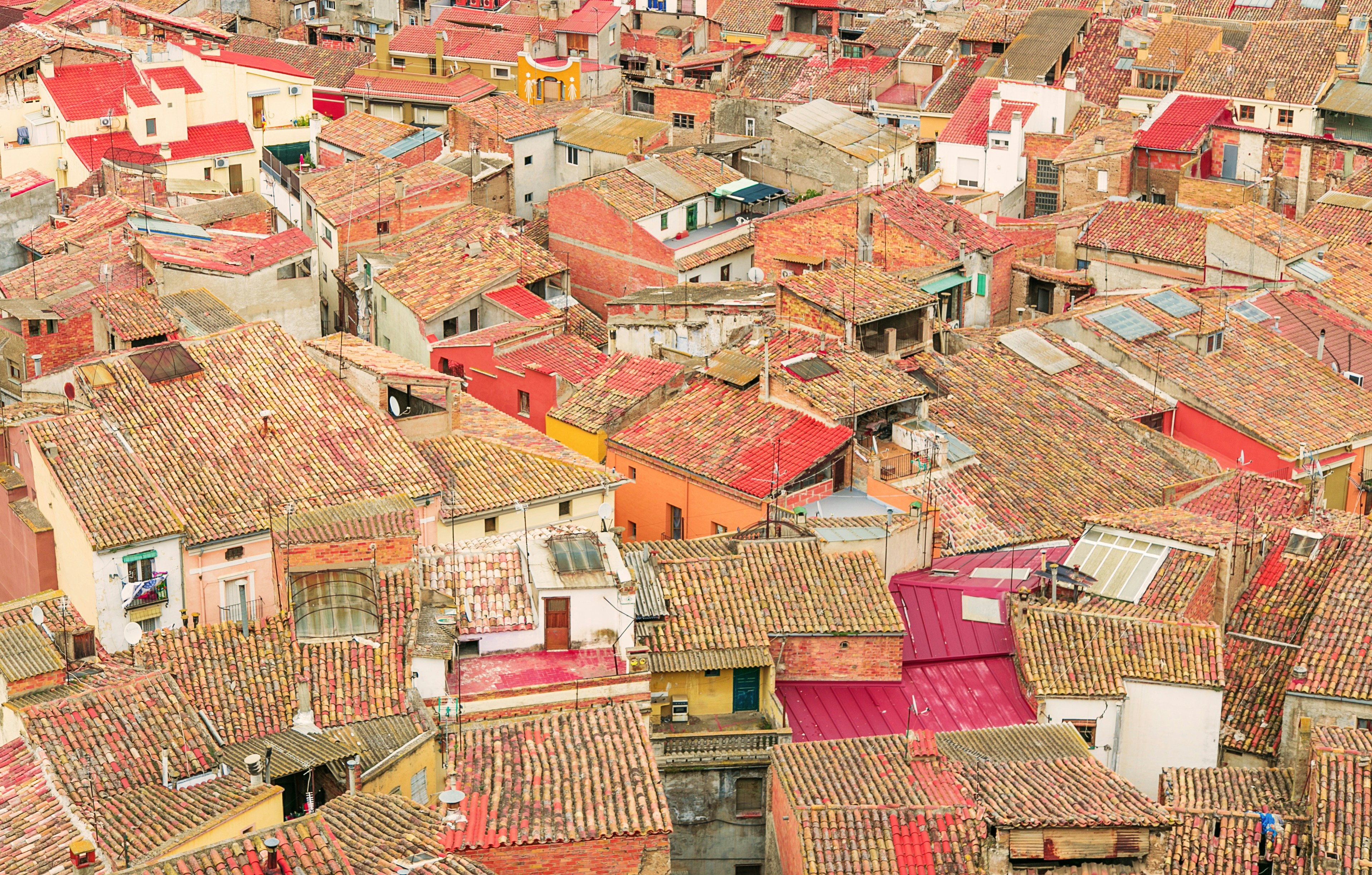 Vibrant rooftops of a quaint town interspersed with colorful tiles and textures, showcasing architectural diversity and charm.
