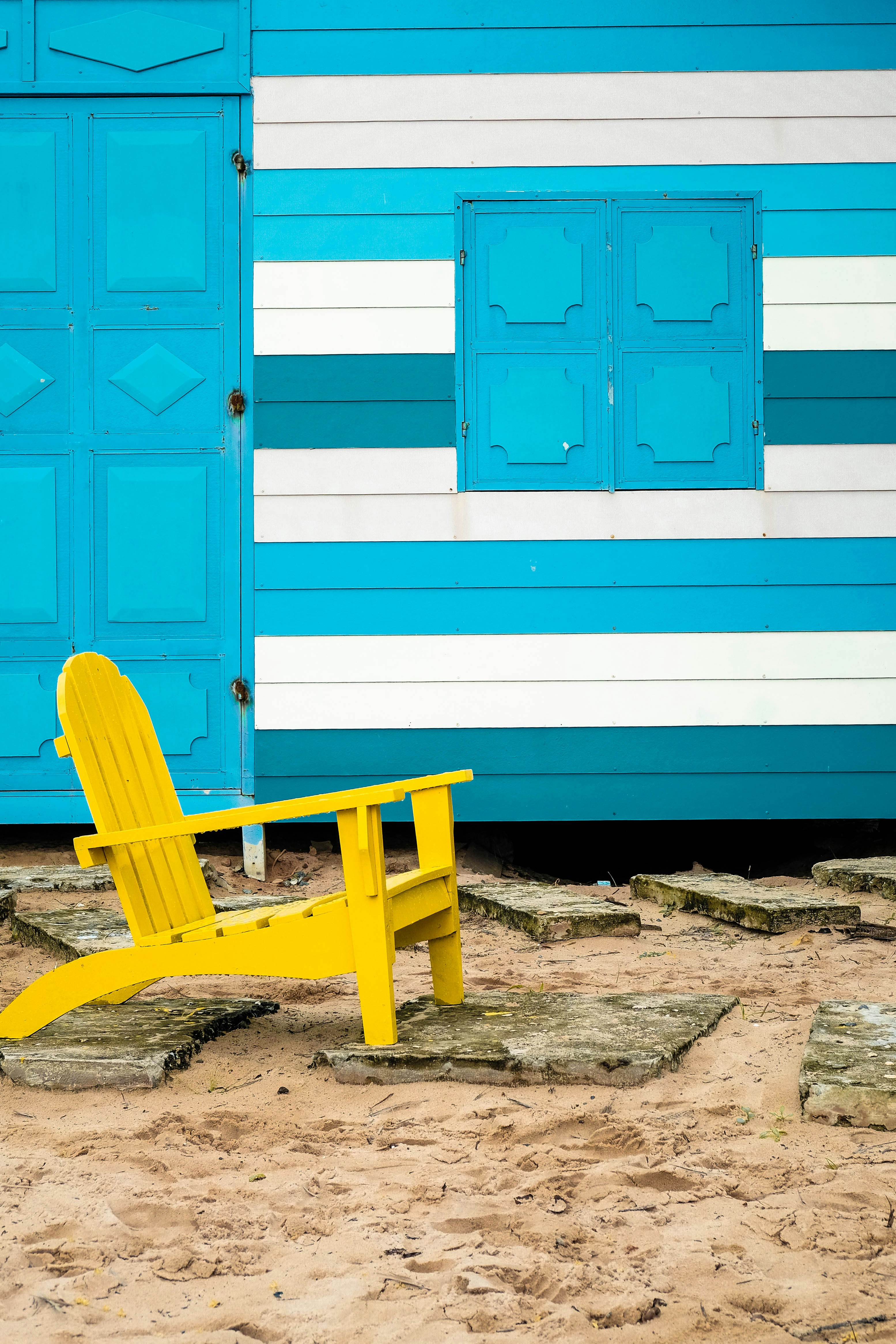 yellow wooden adirondack on brown sand