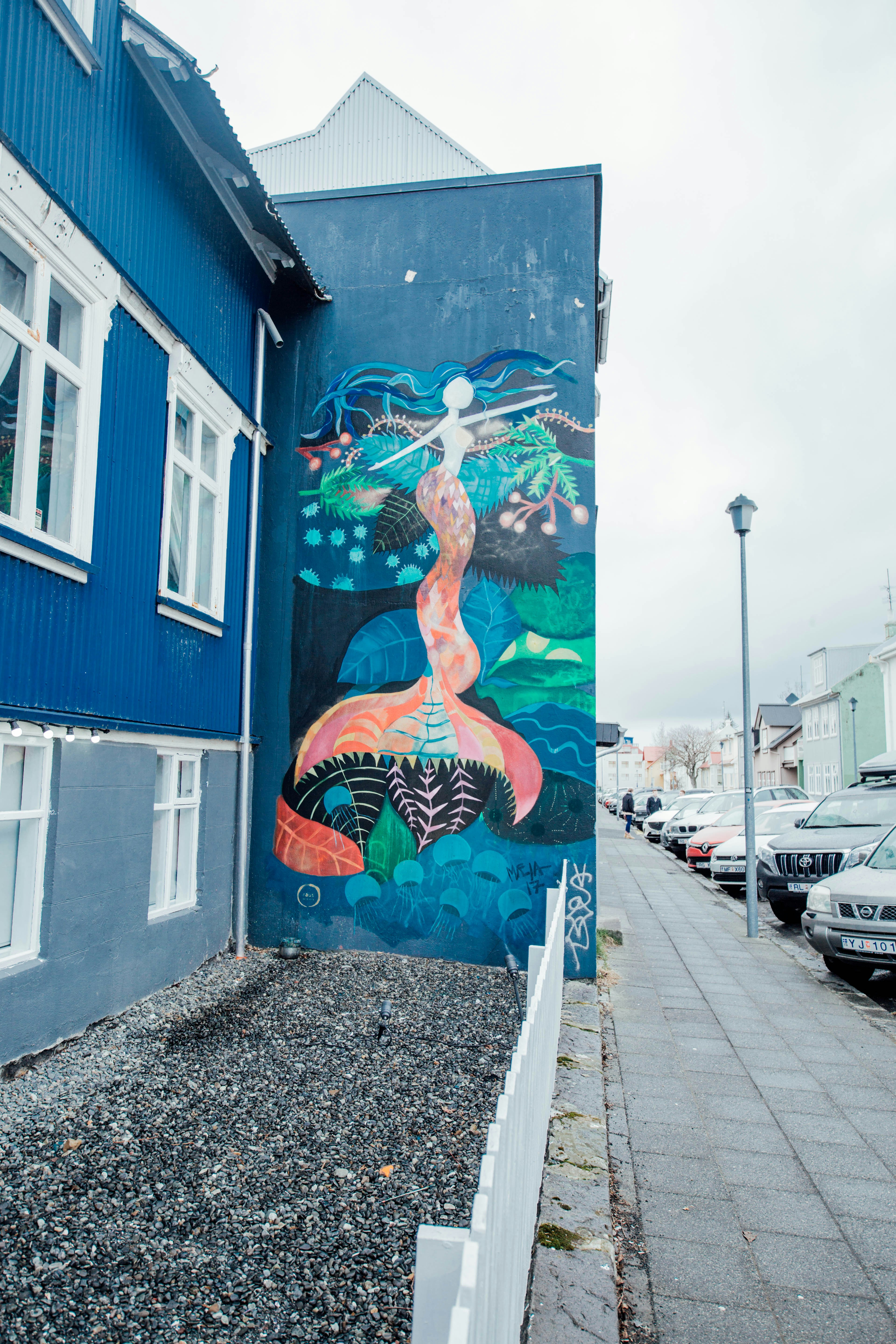 Mermaid on a Blue Wall: A Vibrant Street Mural Reimagining the Quiet Shore