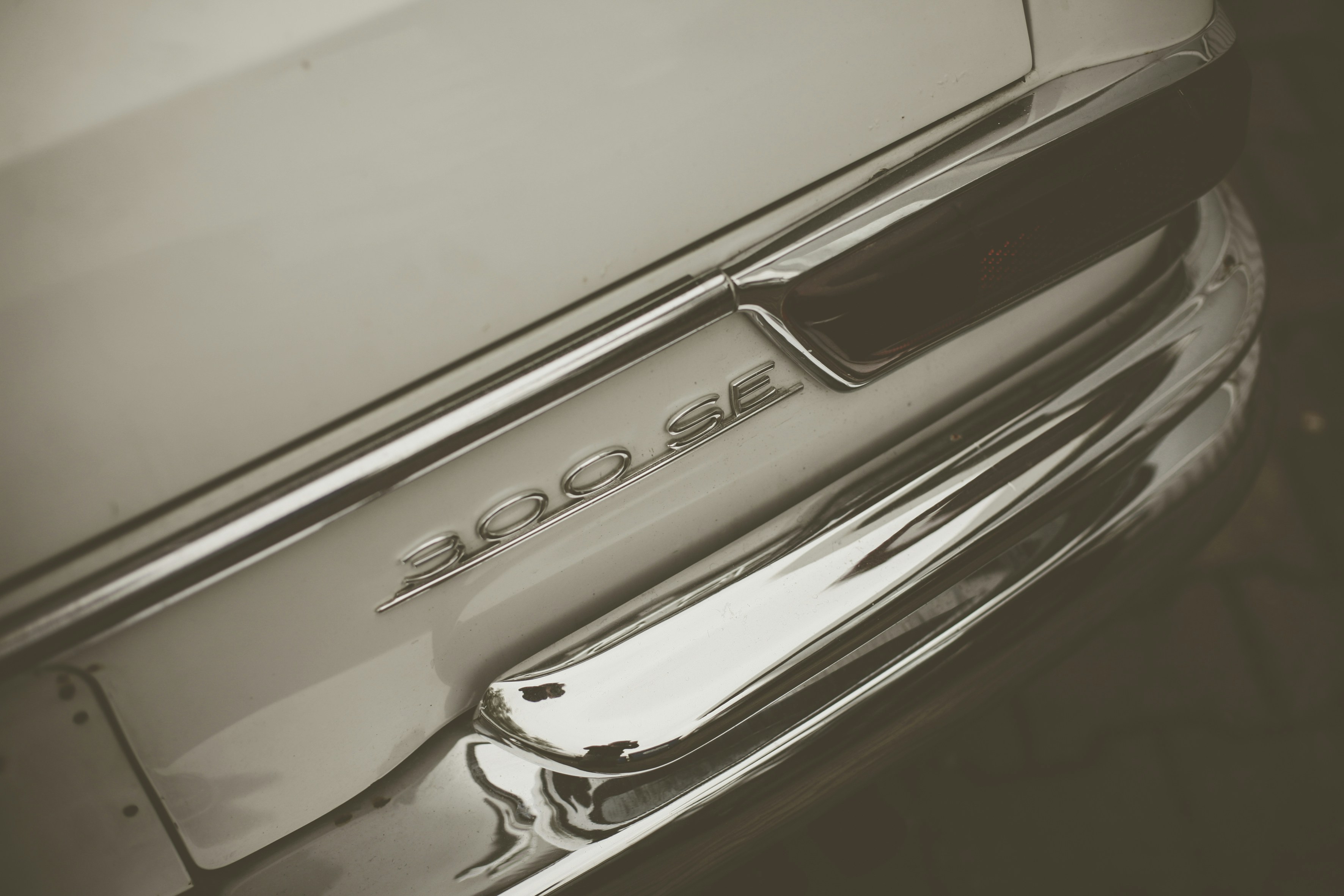 Close-up view of a classic 300 SE's rear detailing, showcasing its chrome accents and emblem. The image highlights the car's vintage design aesthetic.