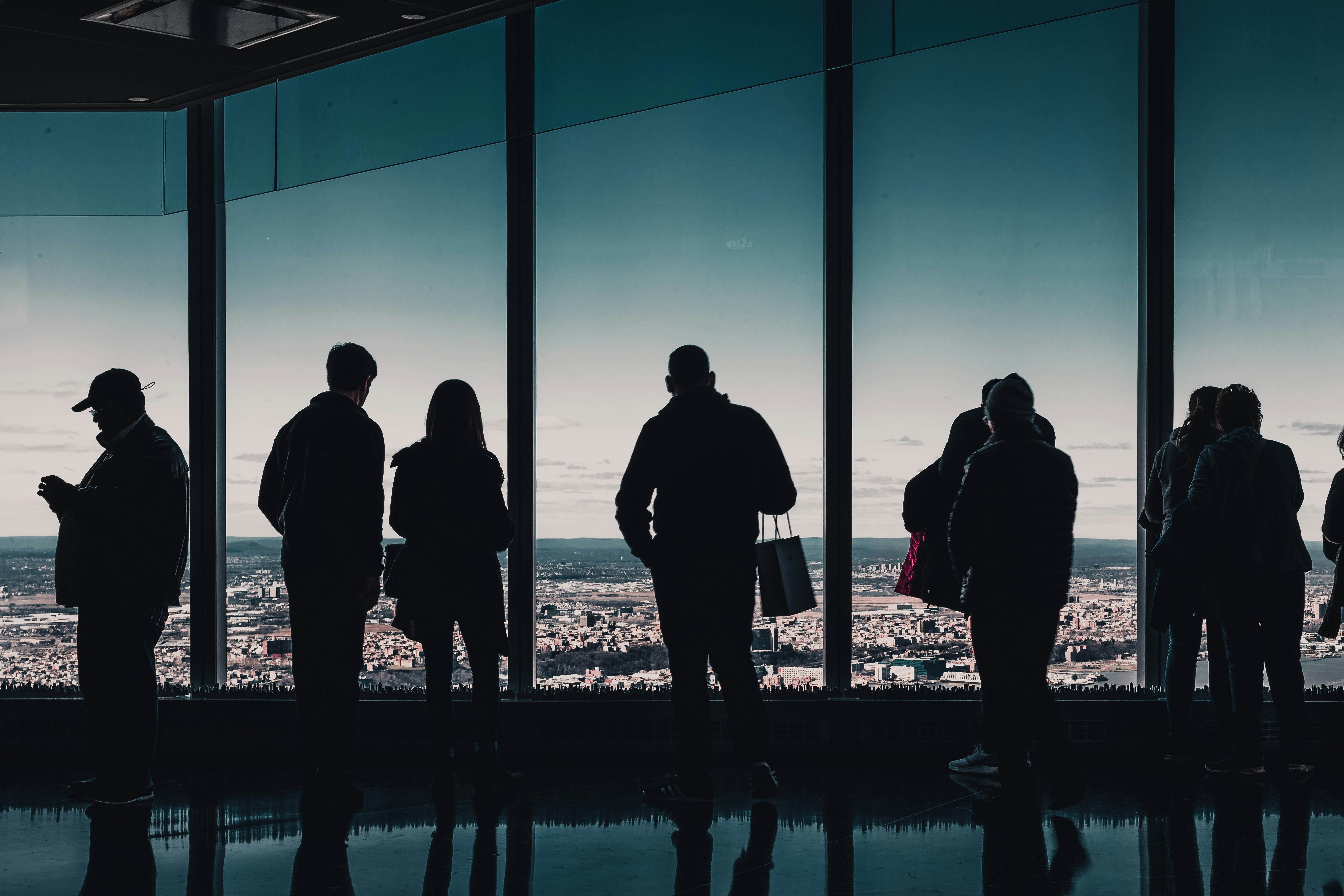 Glass Balcony Gaze: Silhouettes Framing a Distant City at Dusk
