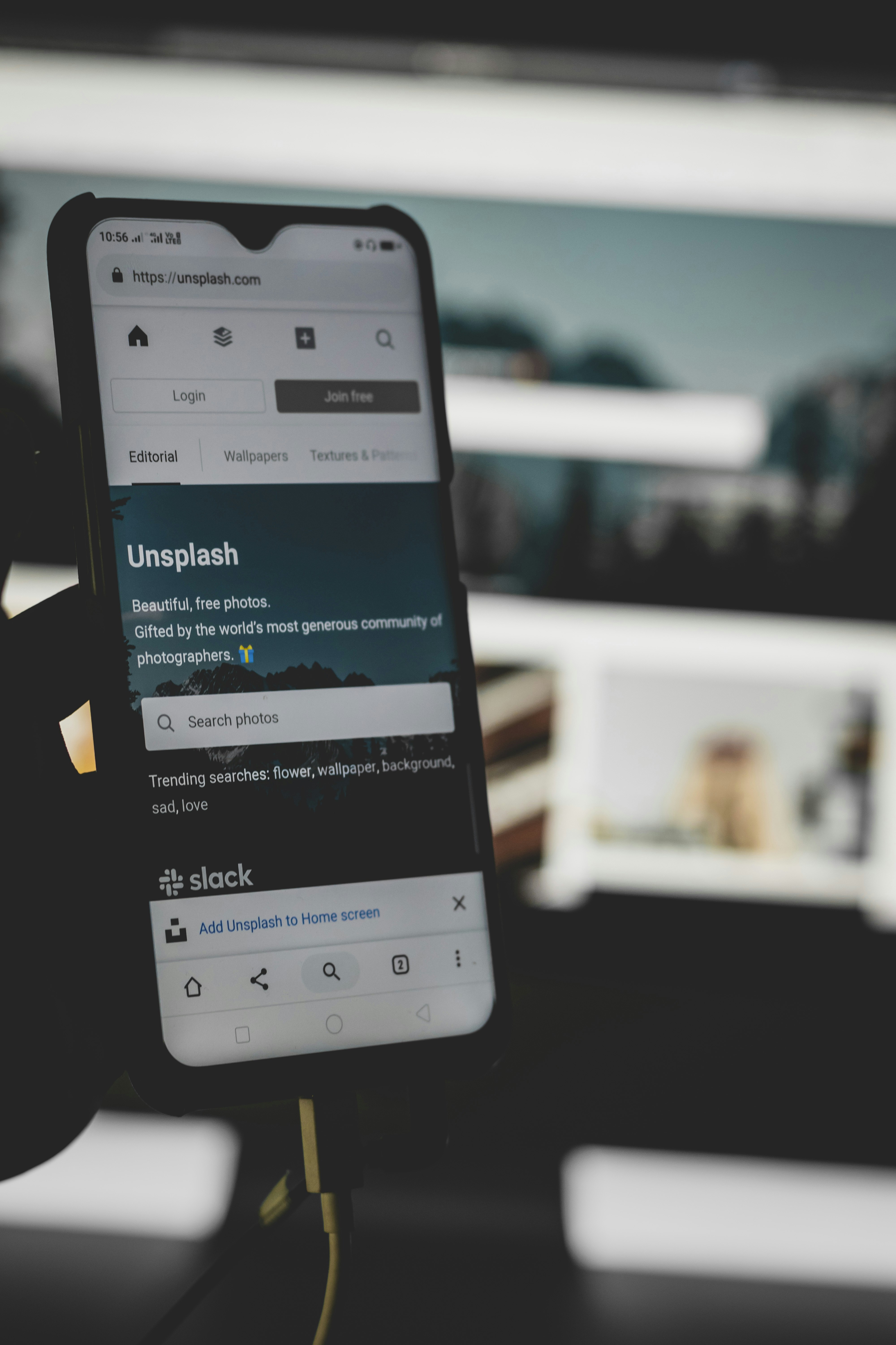 Pocket Portal: Unsplash on a Handheld Screen Amid a Quiet Studio Blur
