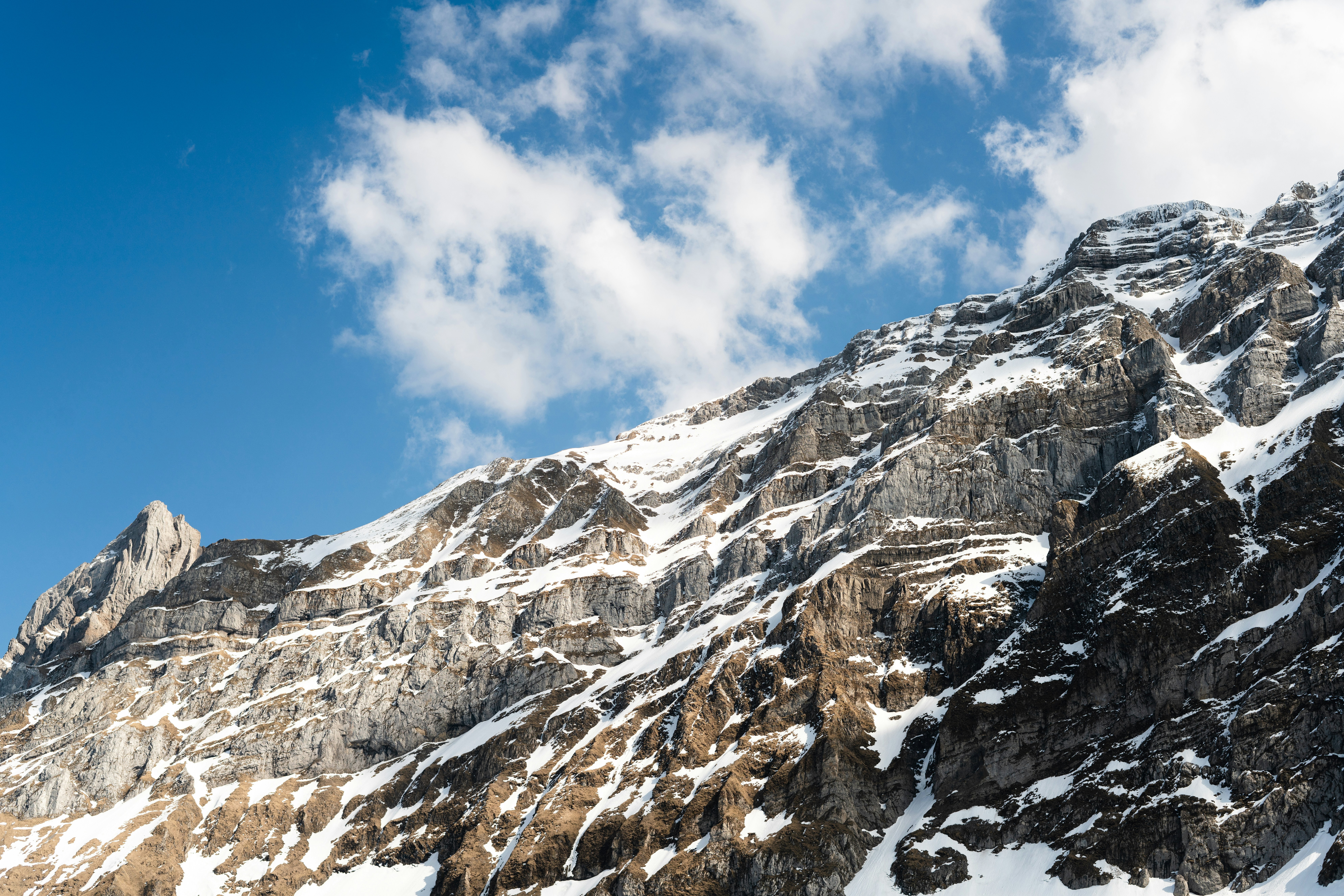 Majestic snow-capped mountains rise against a vibrant blue sky, showcasing the rugged beauty of alpine terrain.