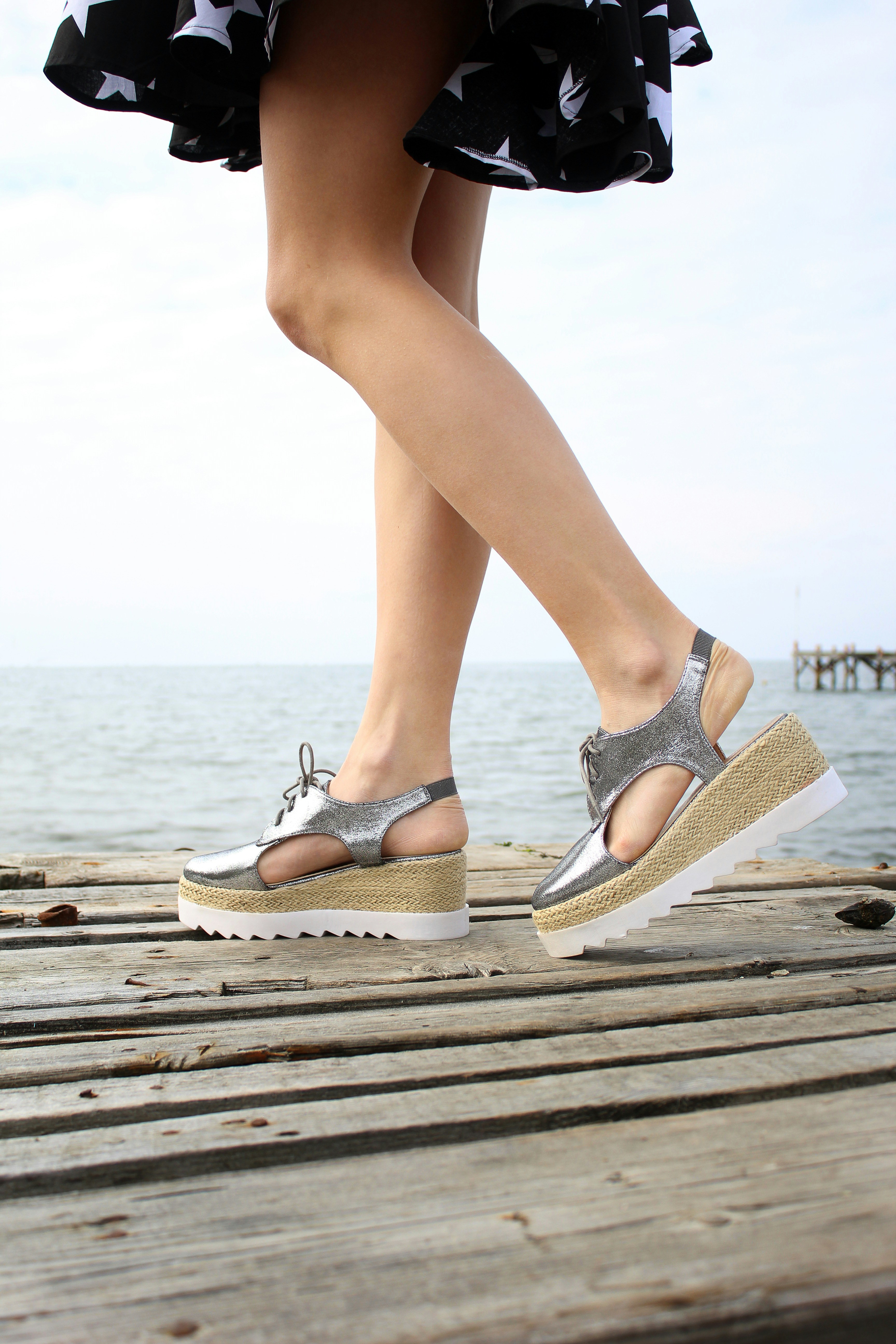 a woman standing on a wooden dock with her legs crossed
