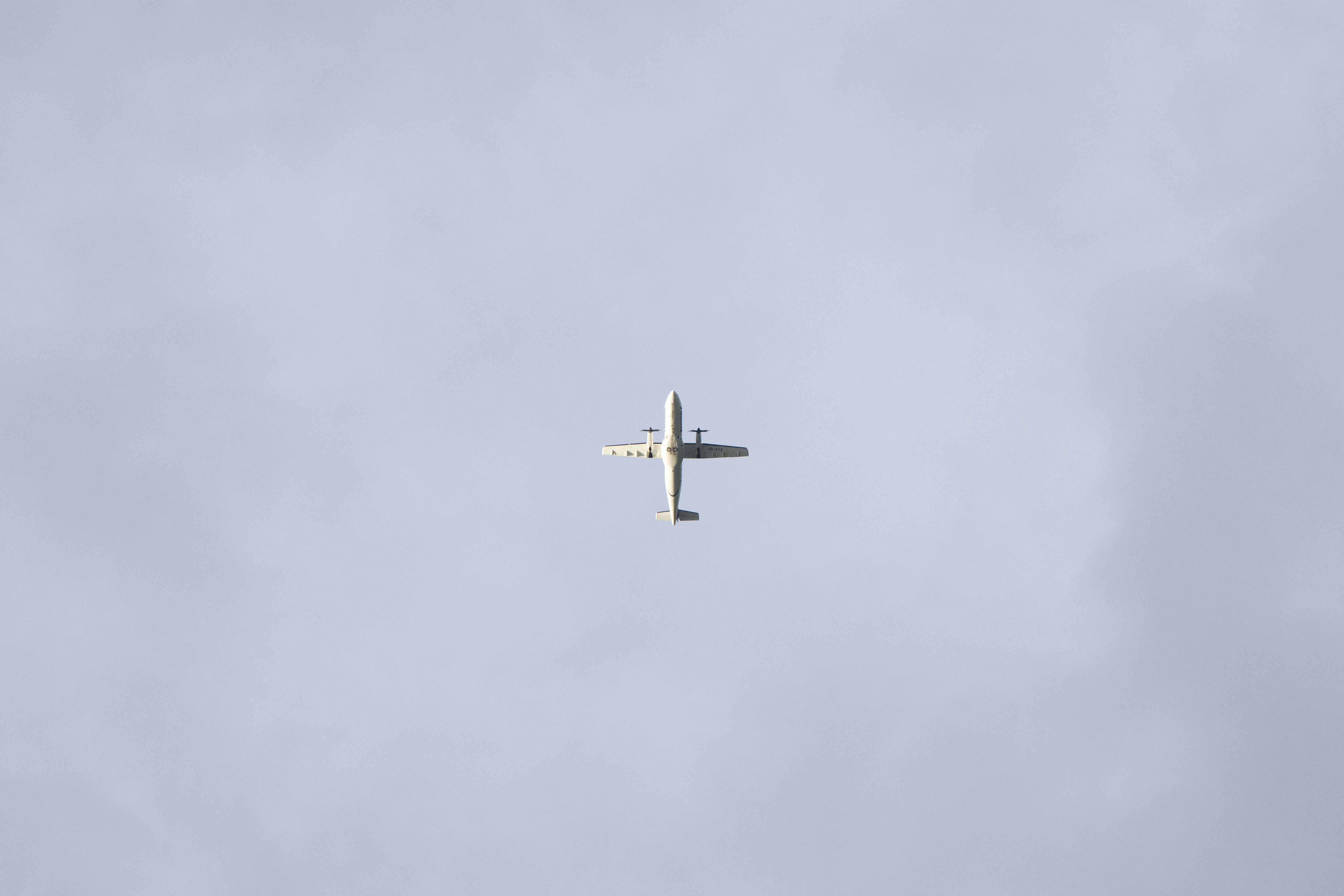 Small aircraft flying high in a cloudy sky, showcasing its sleek design and flight path.