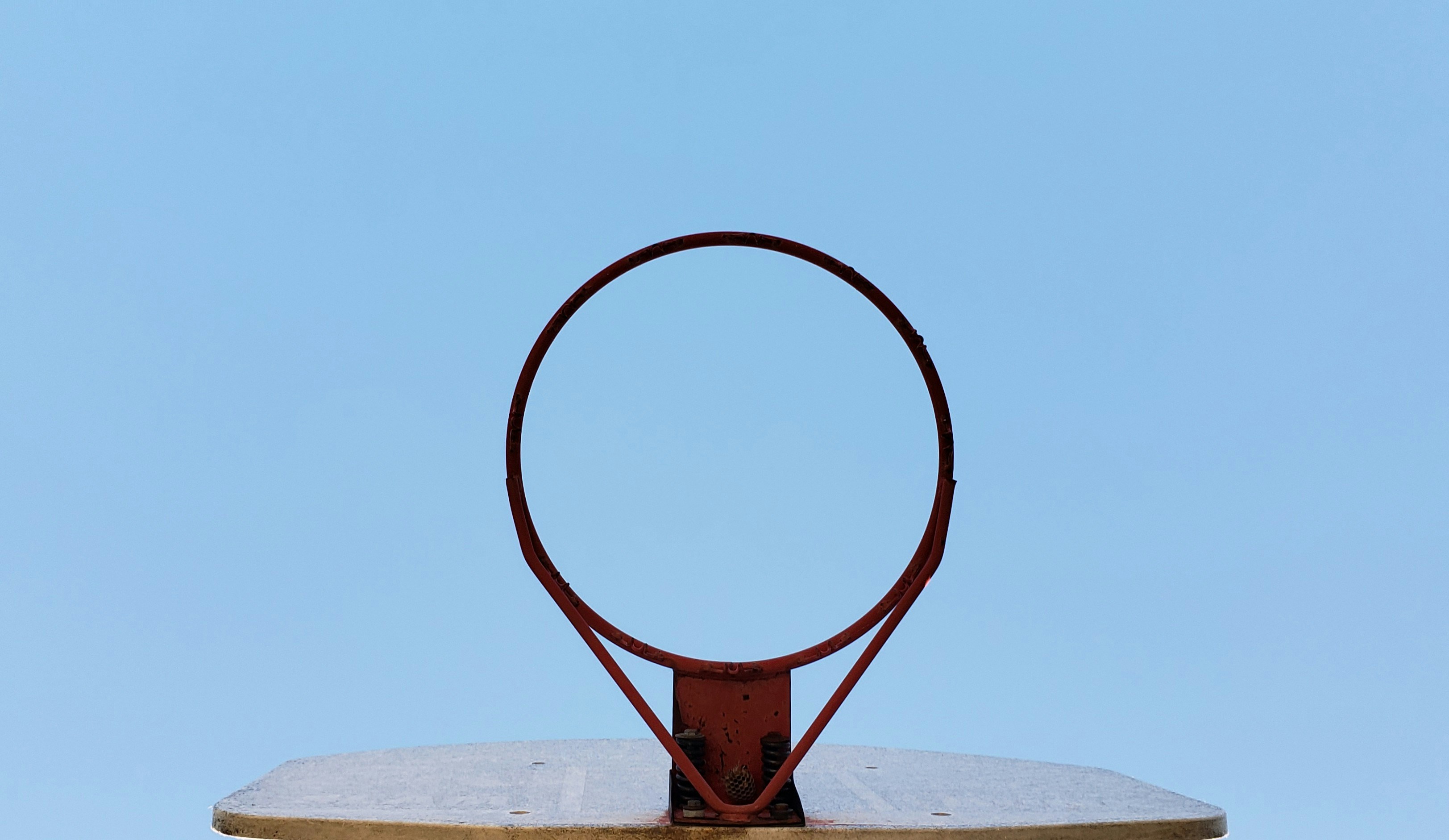 A basketball hoop stands prominently against a clear blue sky, emphasizing the simplicity and focus of the game.