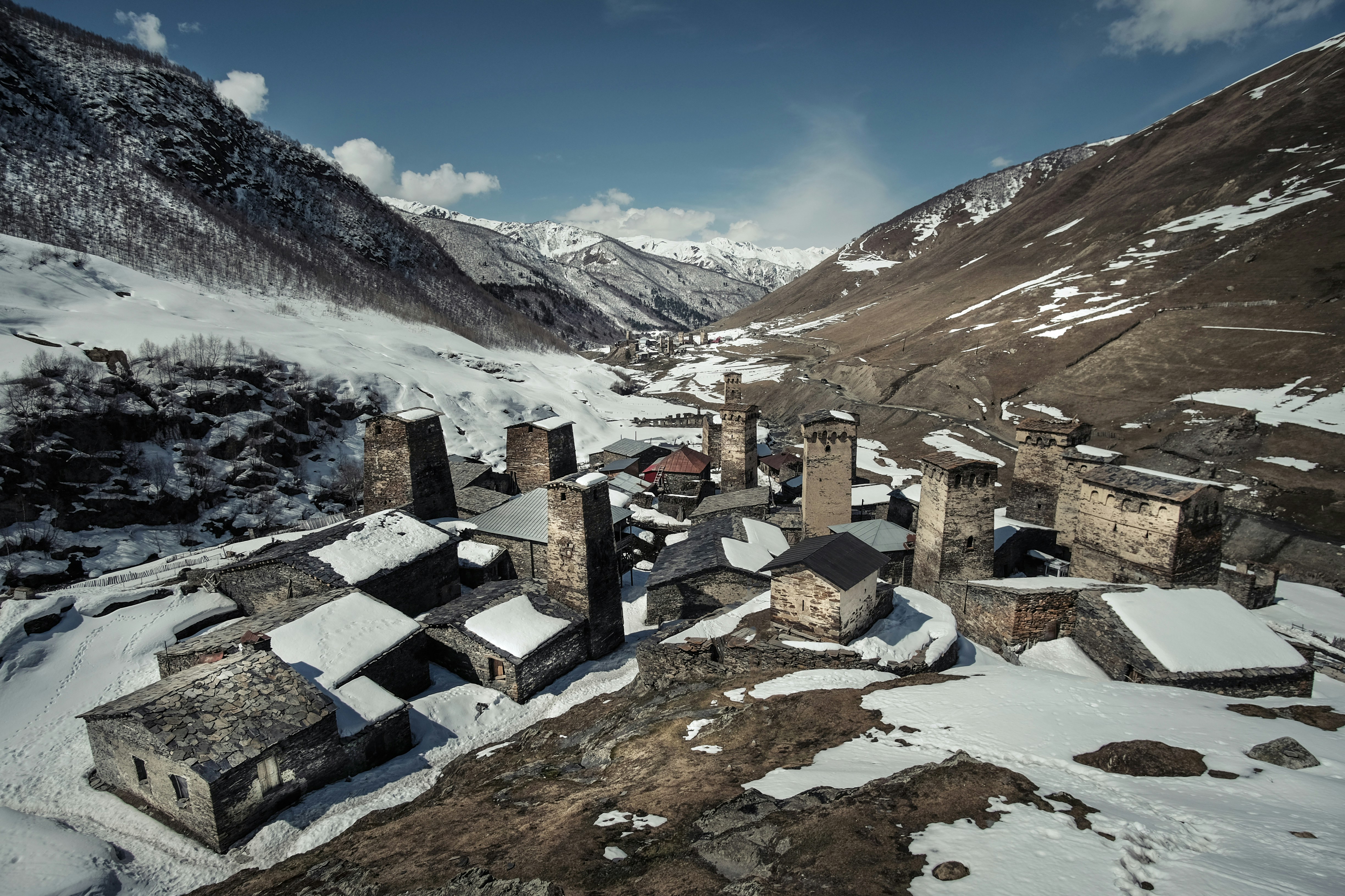 Ushguli | houses near mountain covered with snow under blue and white skies