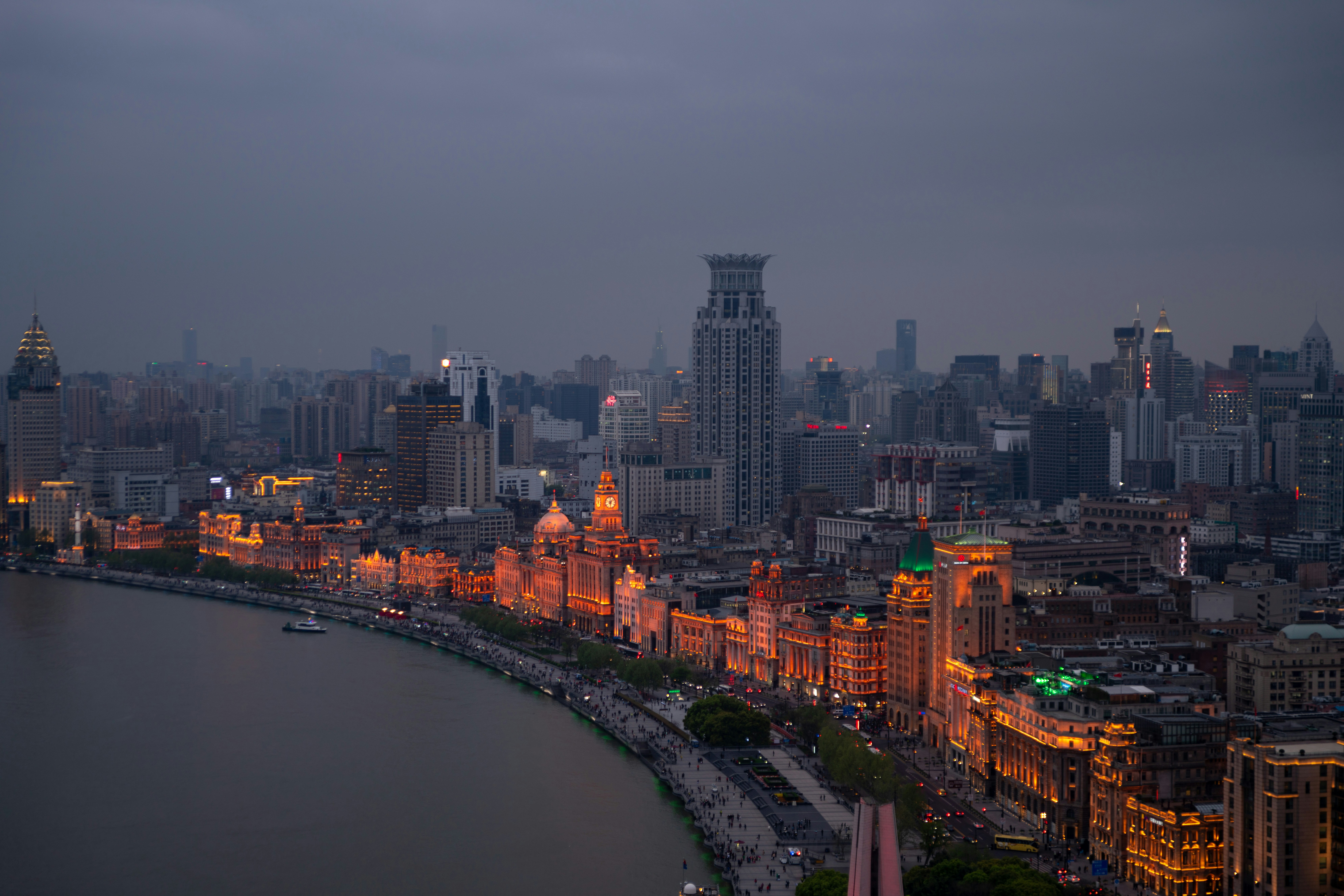 City skyline at dusk with illuminated historic buildings lining the river.