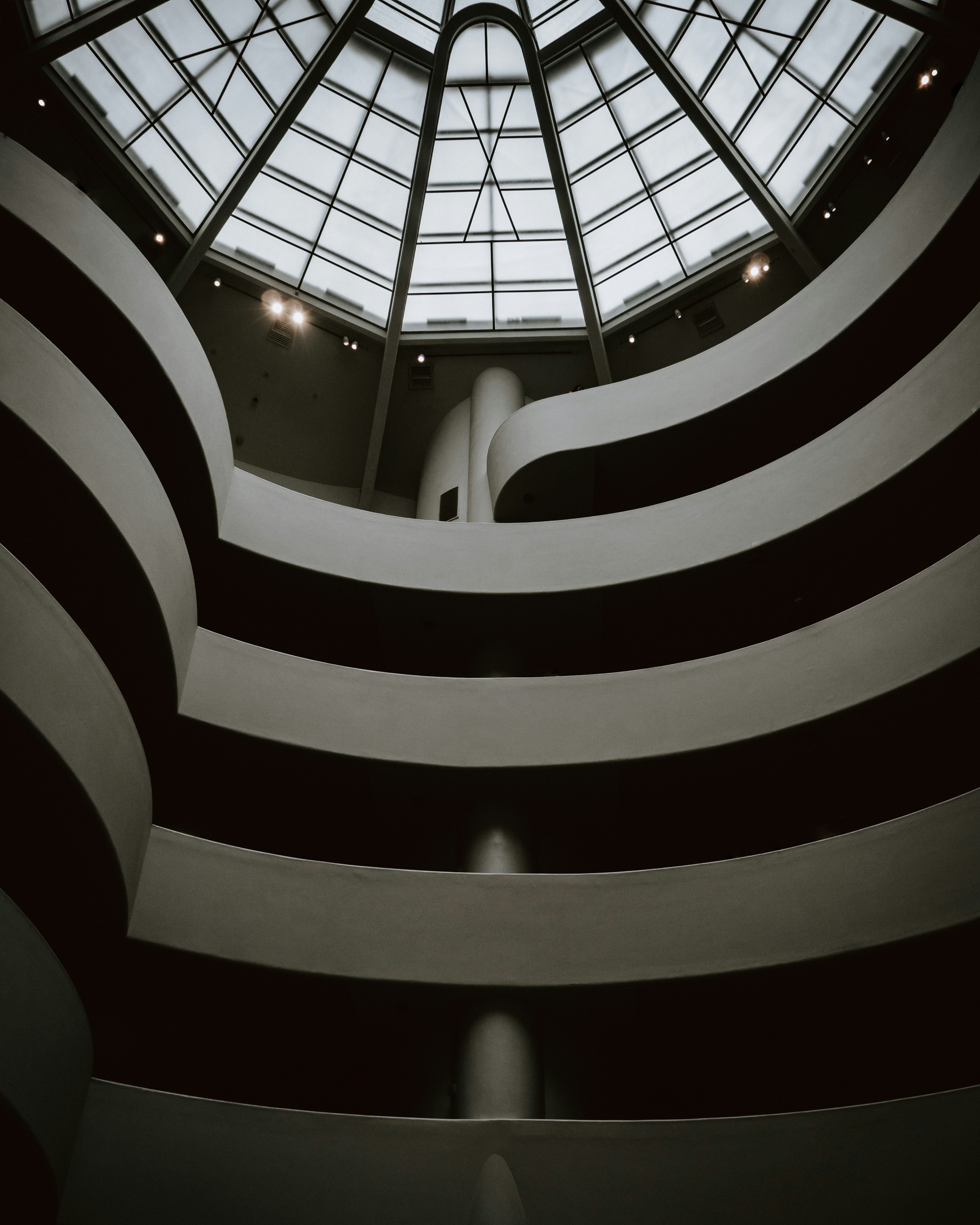 Interior view of a spiral ramp leading up to a glass dome ceiling, showcasing modern architectural design.
