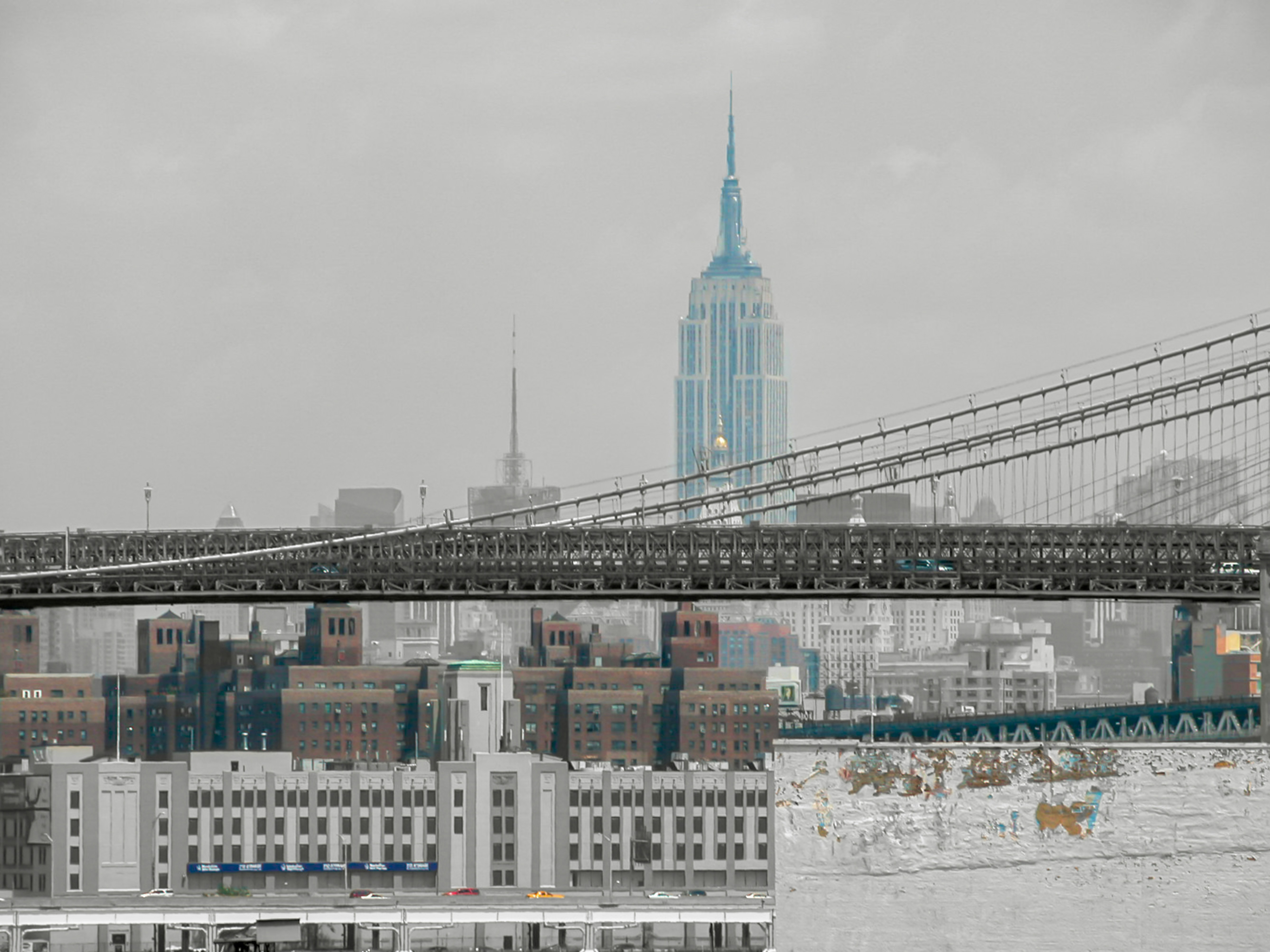 City skyline with the Empire State Building in the distance, viewed over a bridge, in a desaturated, documentary-style scene.