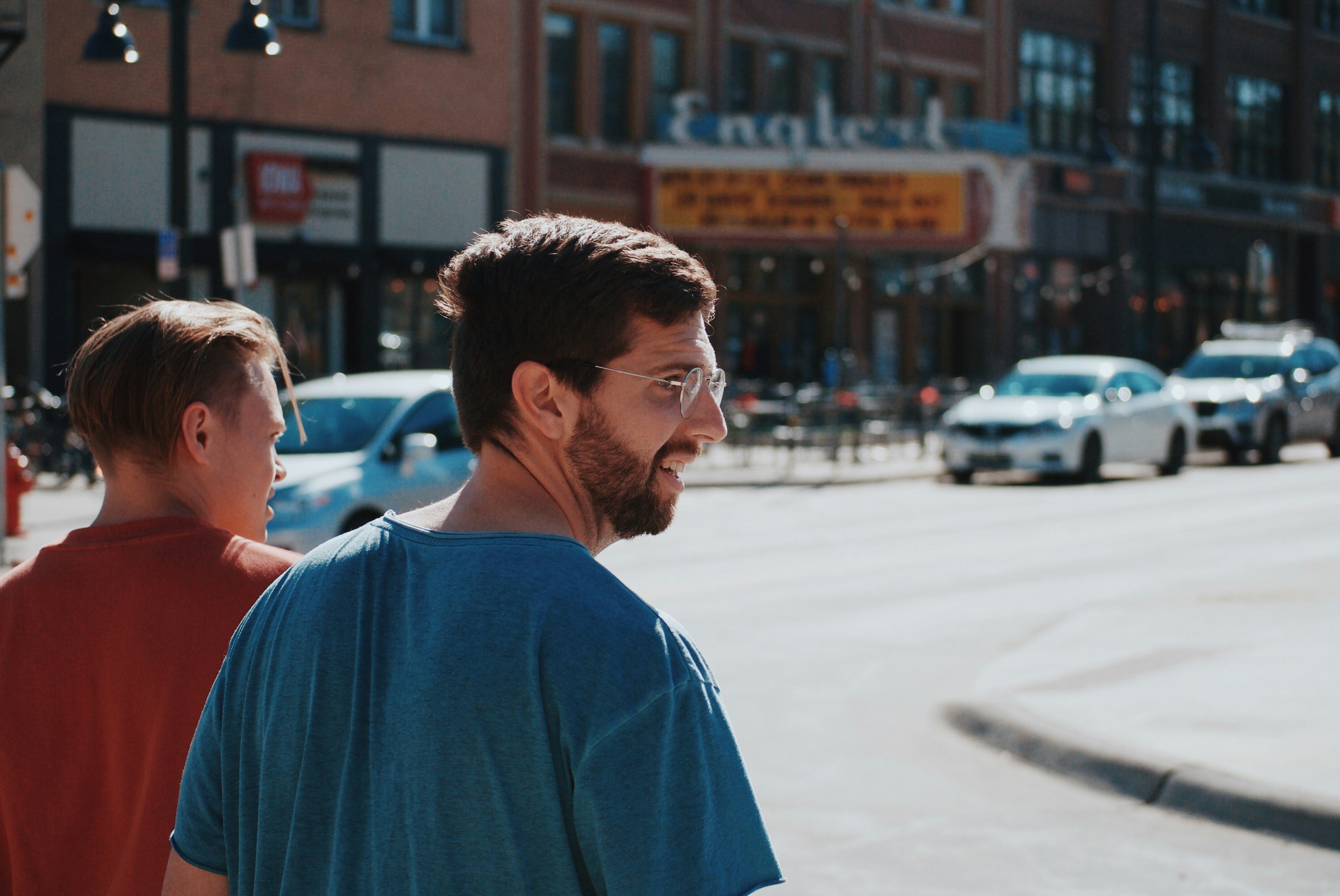 Two friends walking through a bustling city street, with a theater marquee in the background hinting at evening entertainment.