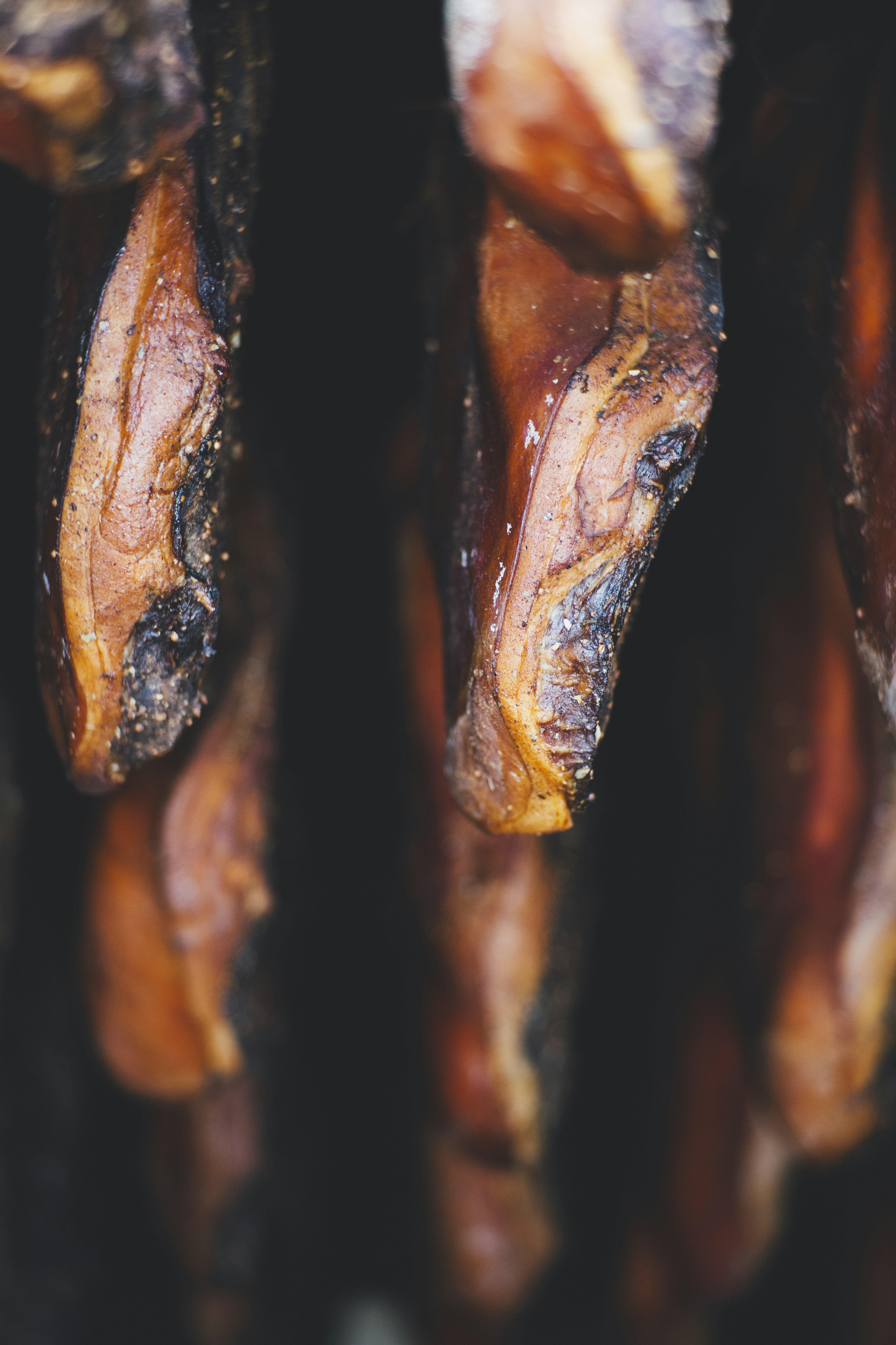 Cured Threads: Close-Up of Charred Bacon Ribbons in Ember Haze