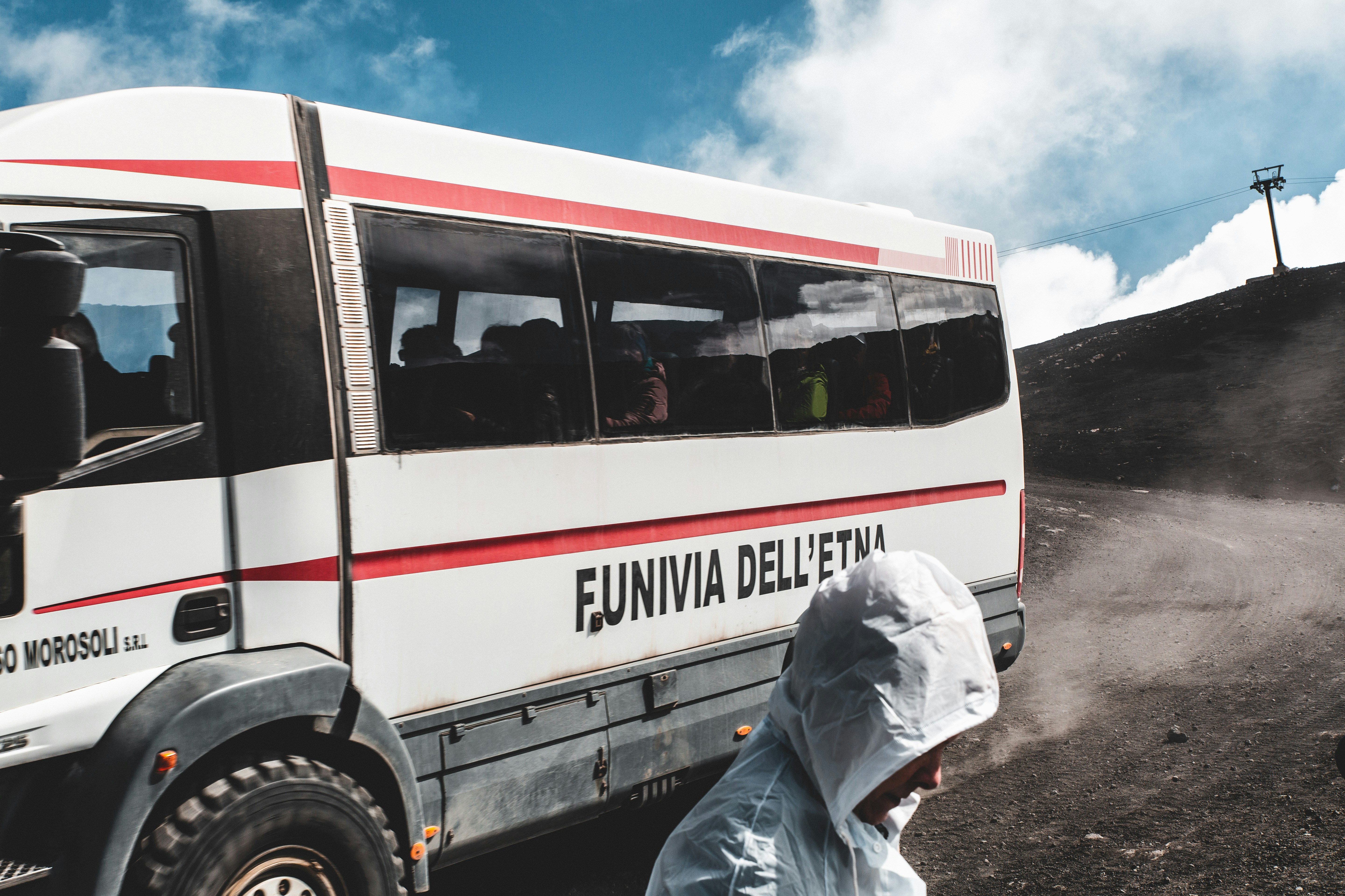 Quarry Daylight: A White Bus, Red Stripe, and a Hoodie in the Foreground