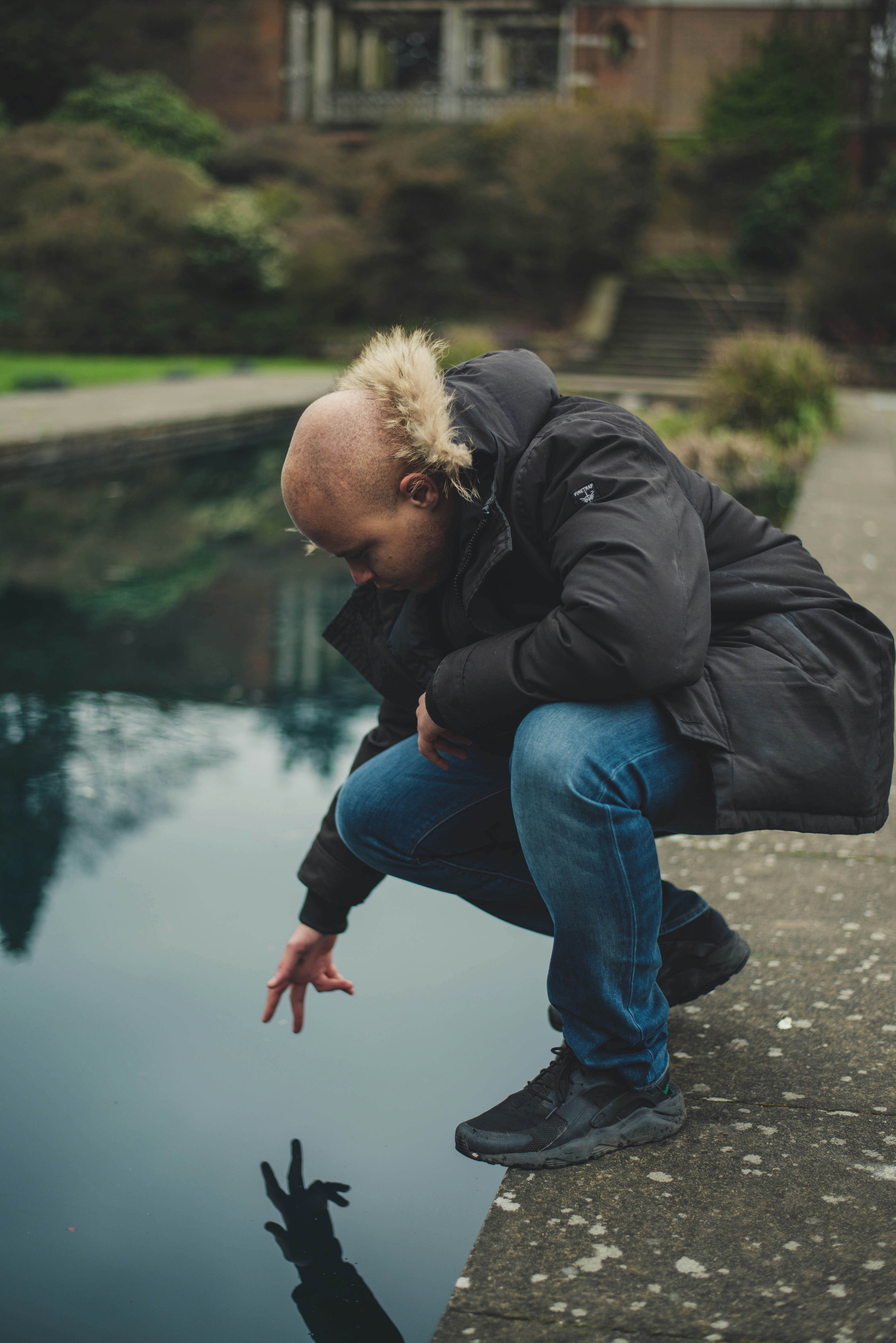 Contemplative Reach: A lone figure extends toward the water’s edge