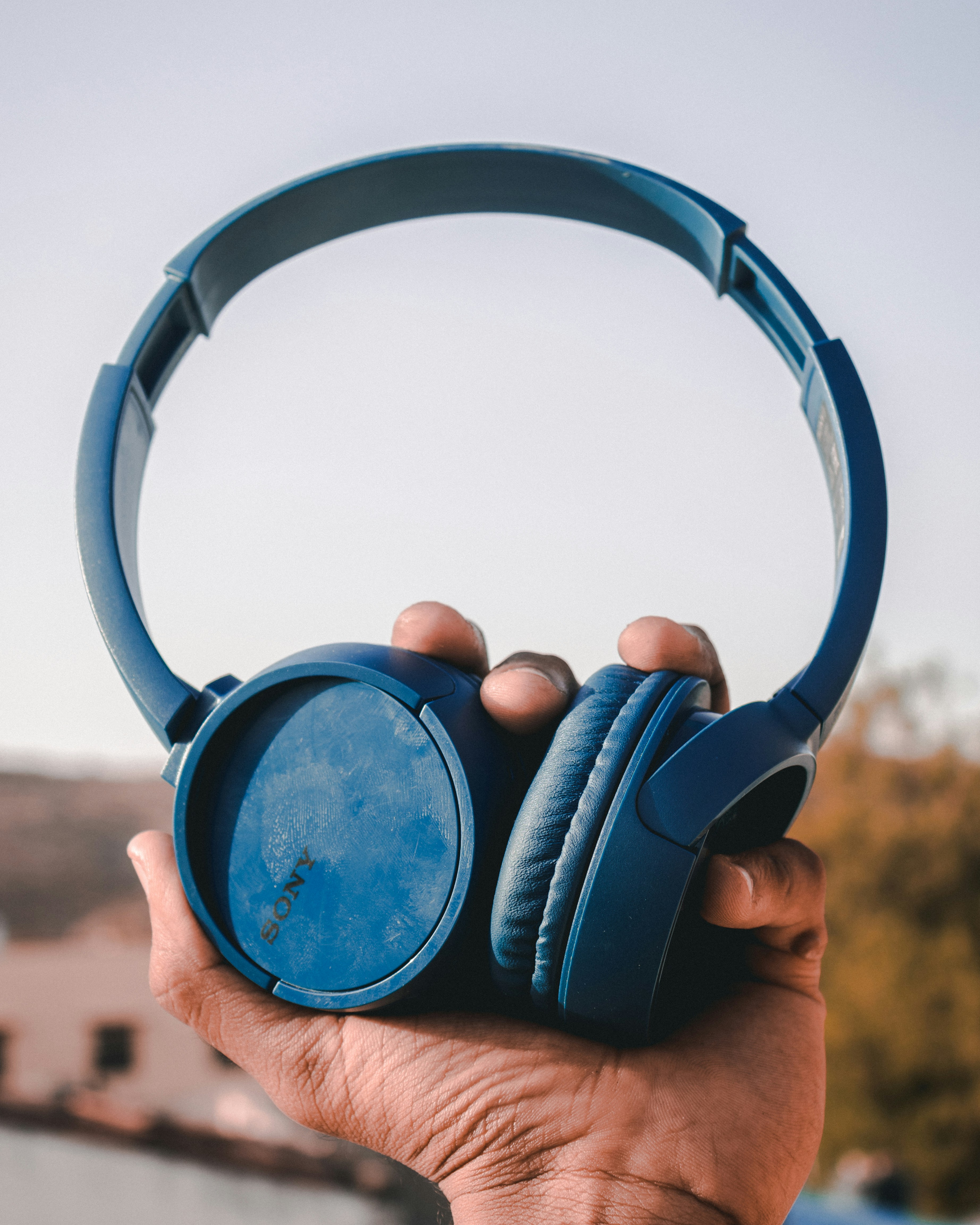 Azure Over-Ear in Hand: Colorful Headphones Framed by Soft Outdoor Blur