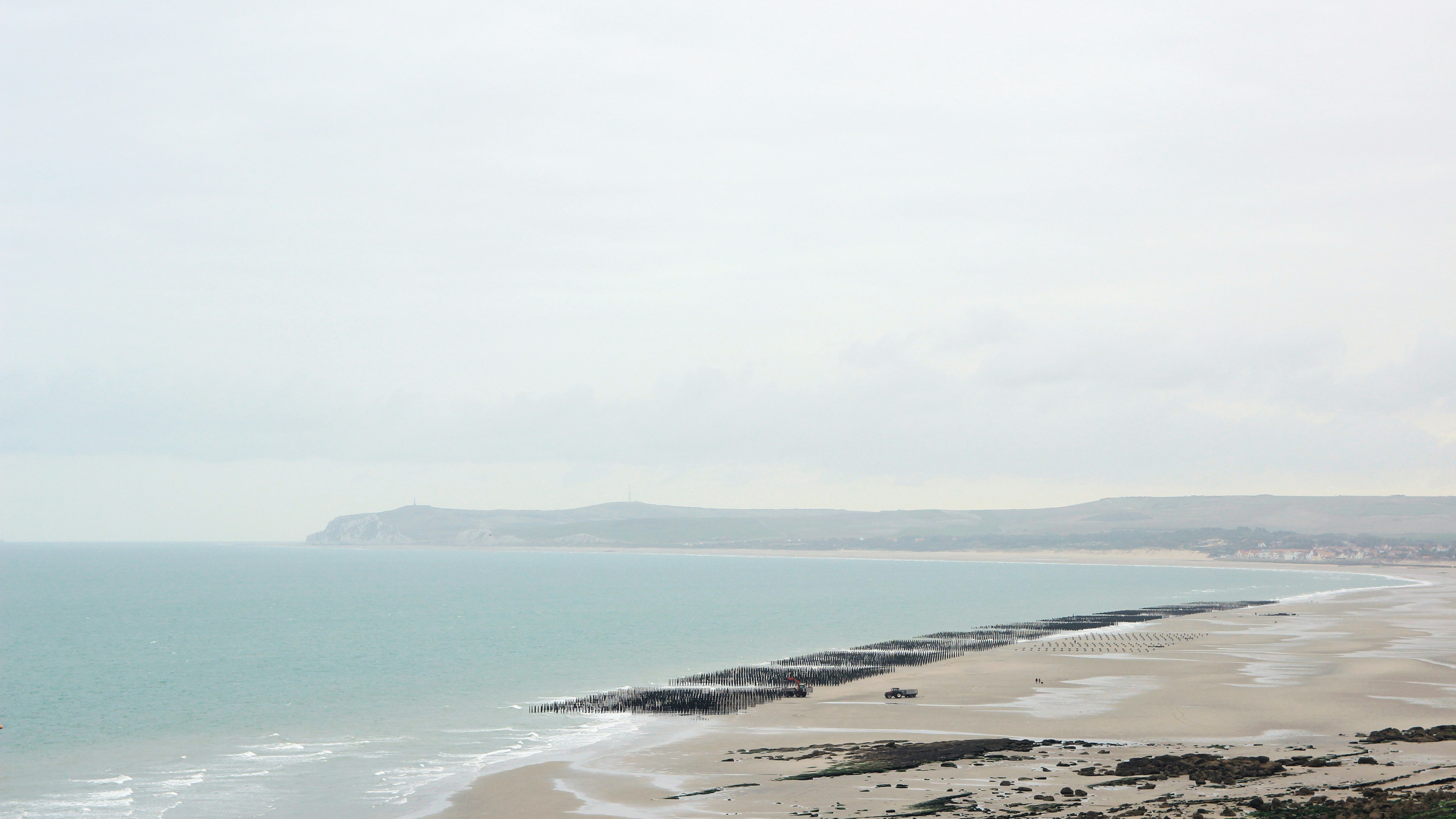 Expansive sandy beach with gentle waves under a cloudy sky.