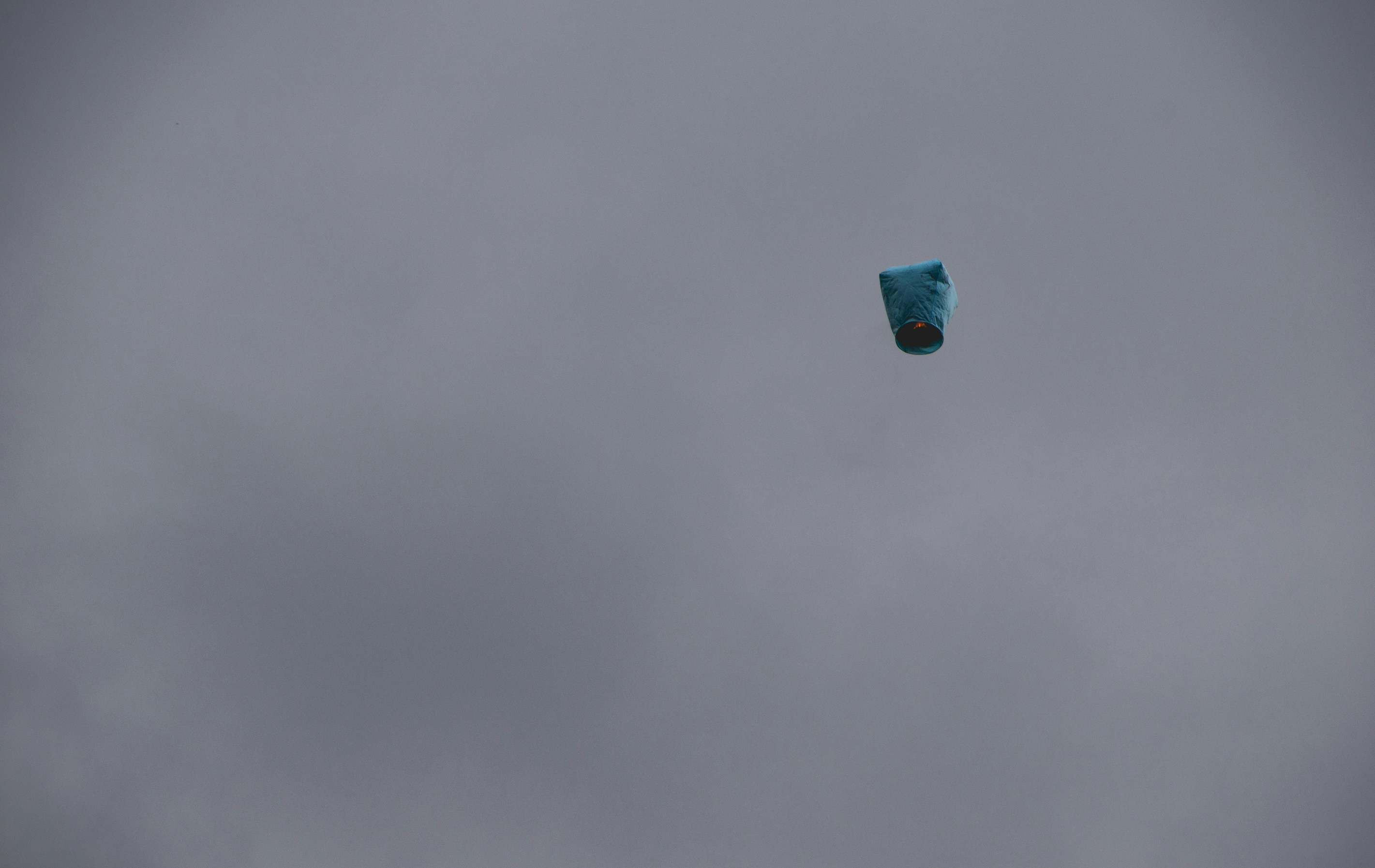 a blue kite flying in a cloudy sky