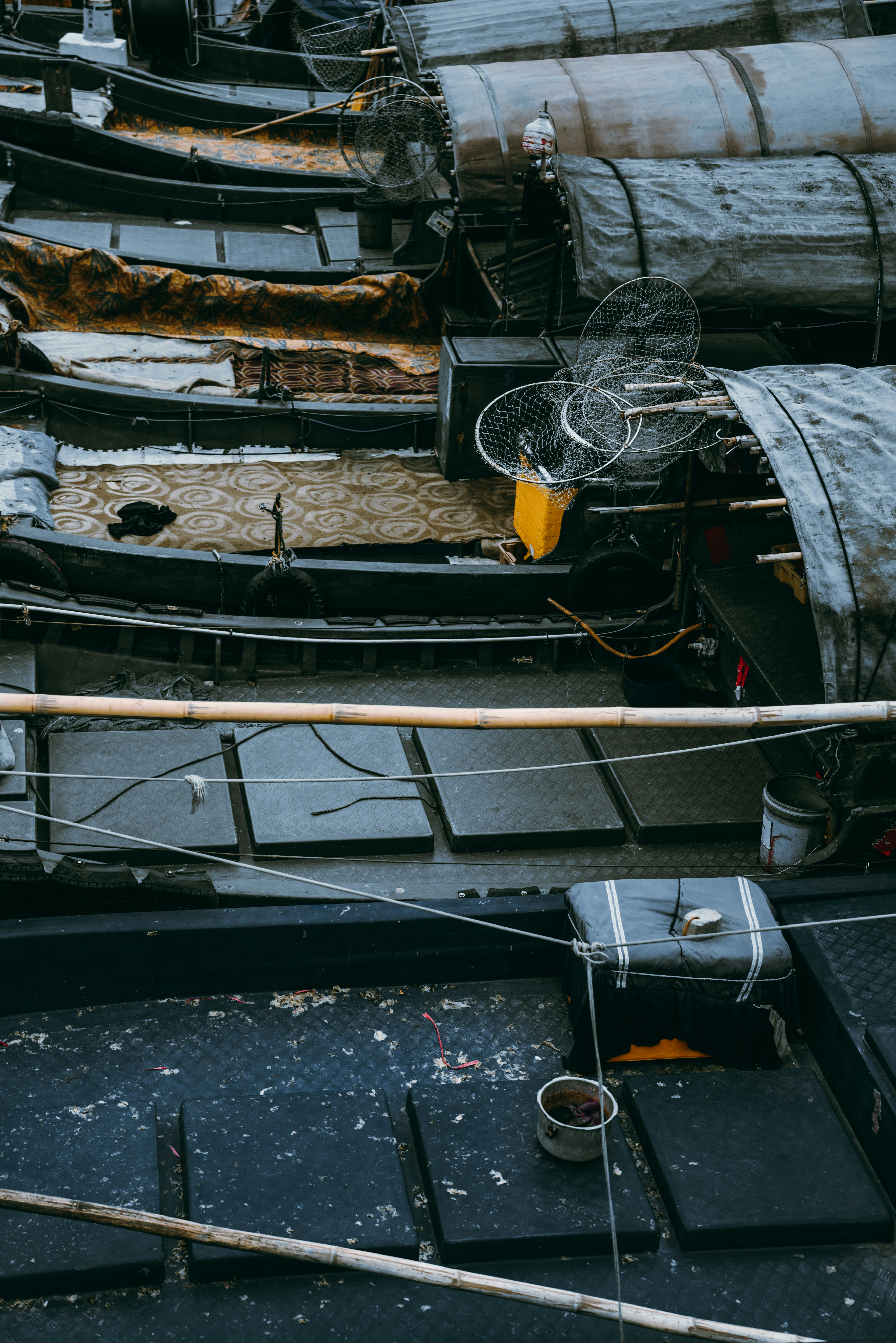 Aerial view of several boats arranged closely, showcasing unique patterns and textures on their surfaces. The scene captures the essence of daily life on the water.