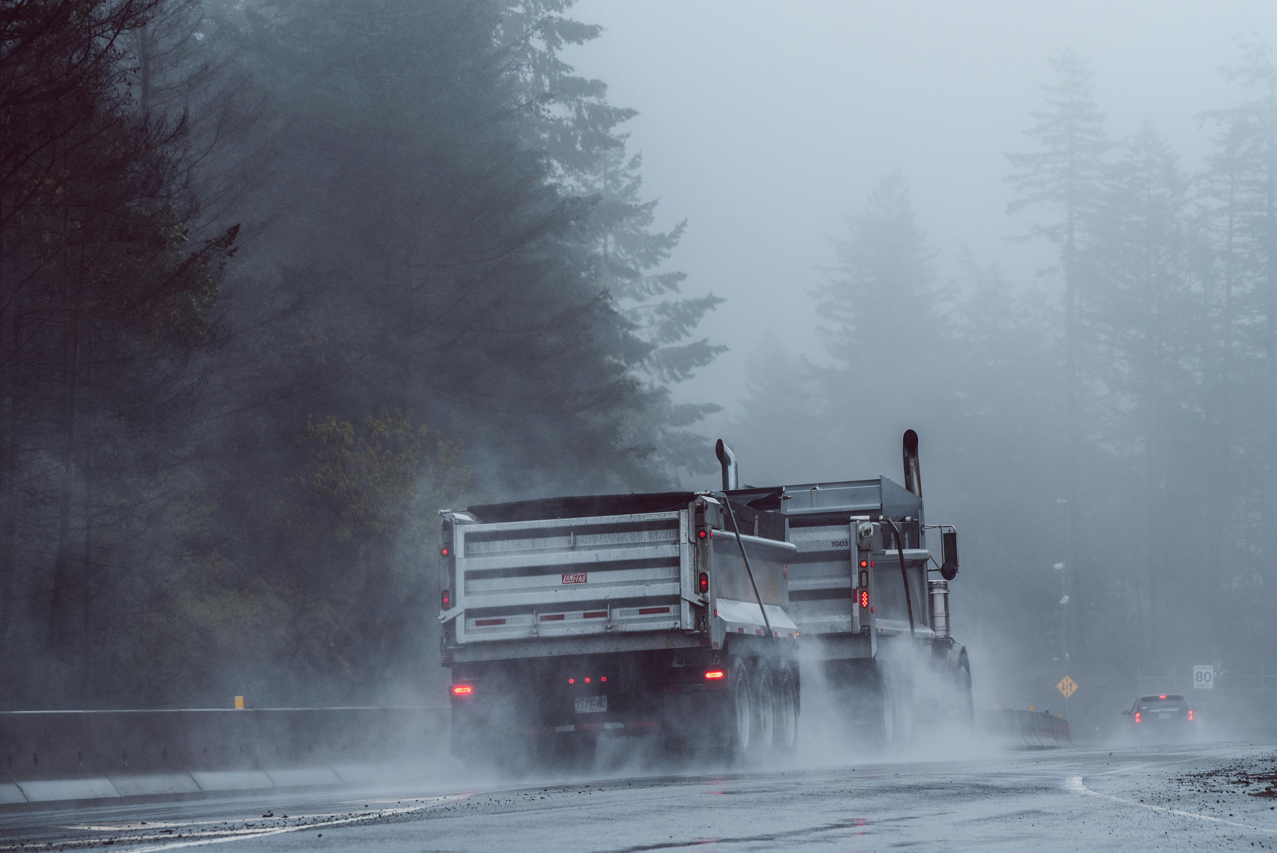Rain-Swept Hauler through Fog: A Truck's Echo on the Wet Road