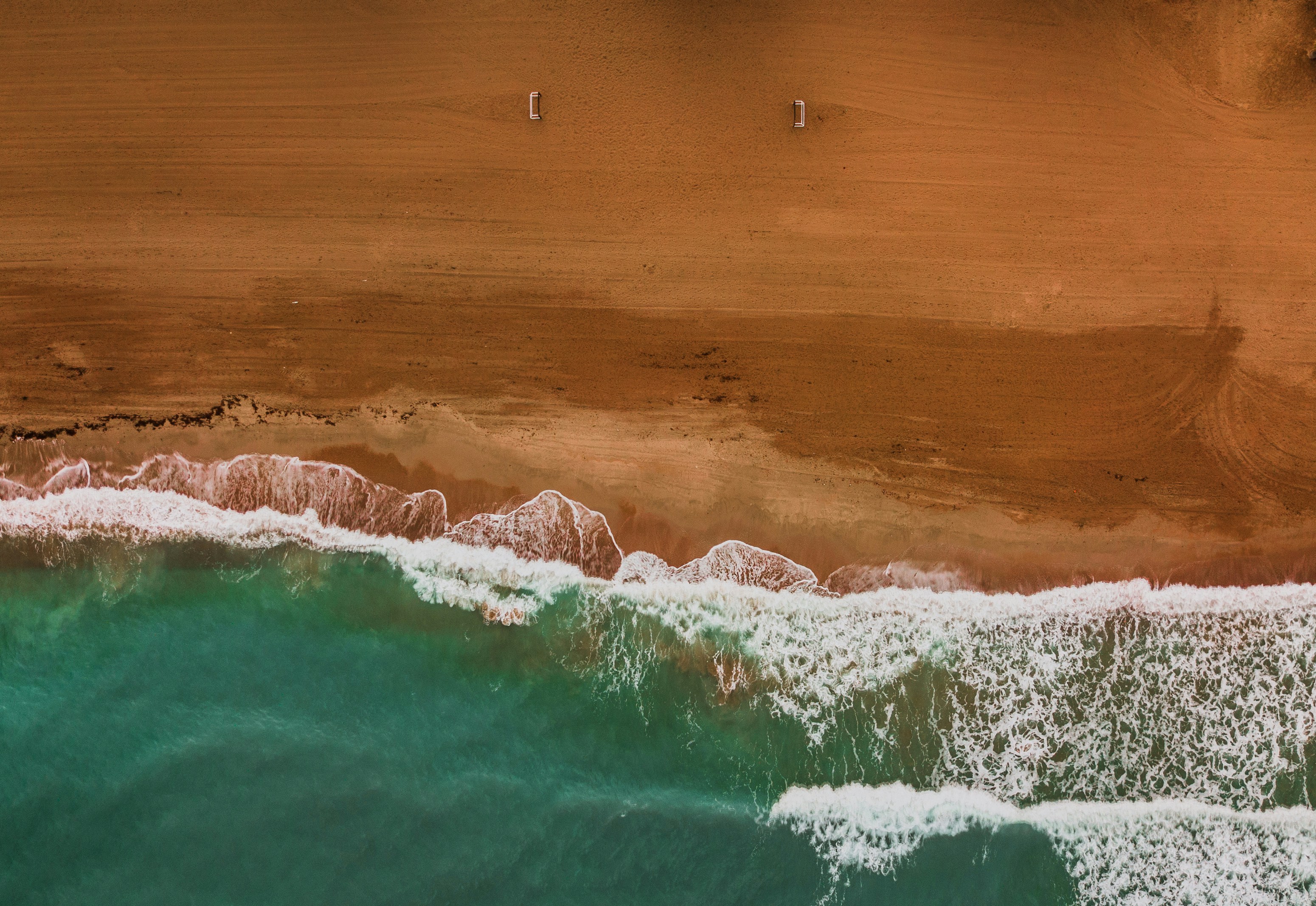 Waves gently lap against a sandy shore, creating a striking contrast of turquoise and amber hues.