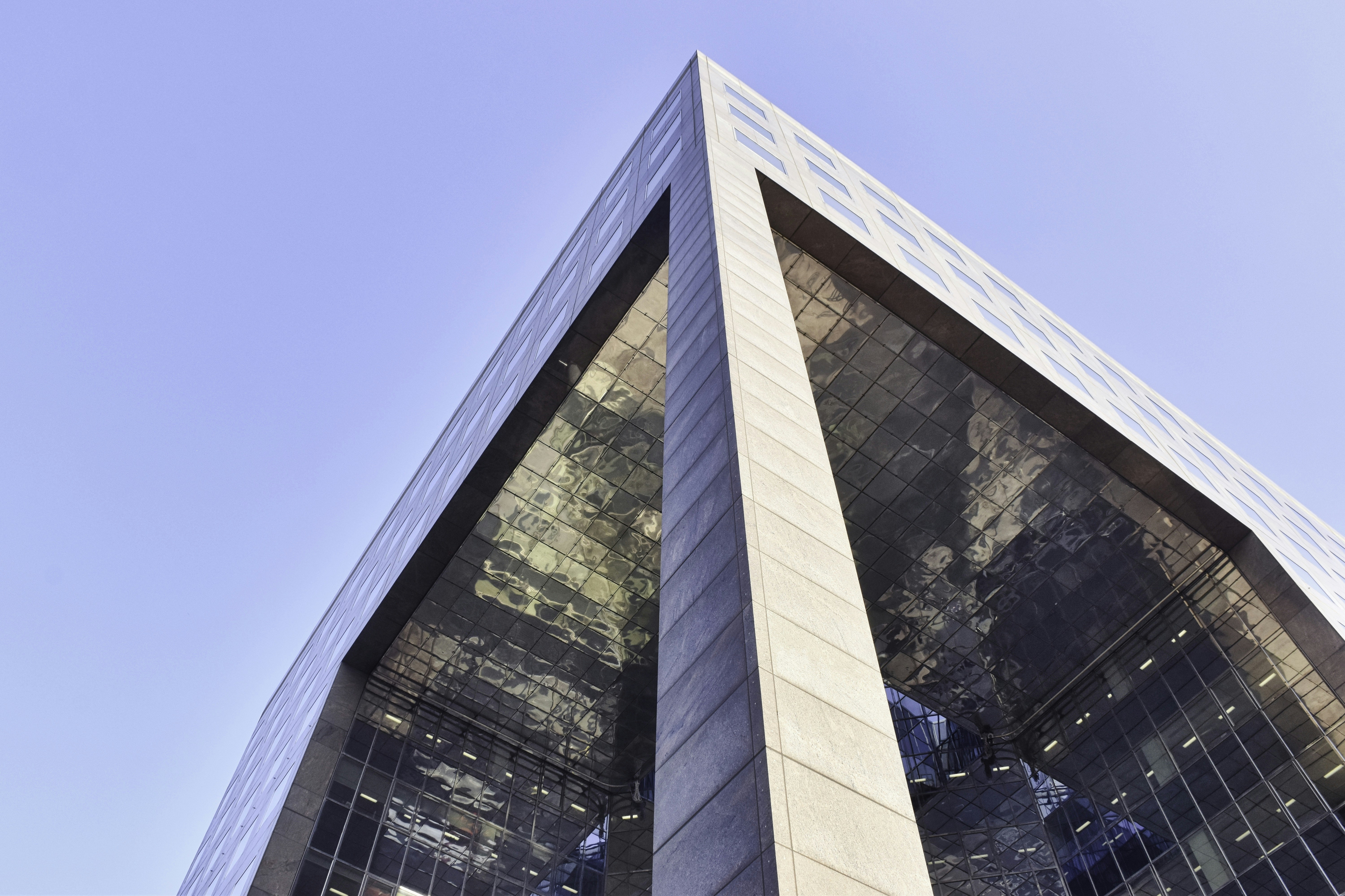 Angular concrete structure reflecting the sky, showcasing contemporary architectural design. The interplay of light and shadows enhances the visual impact.