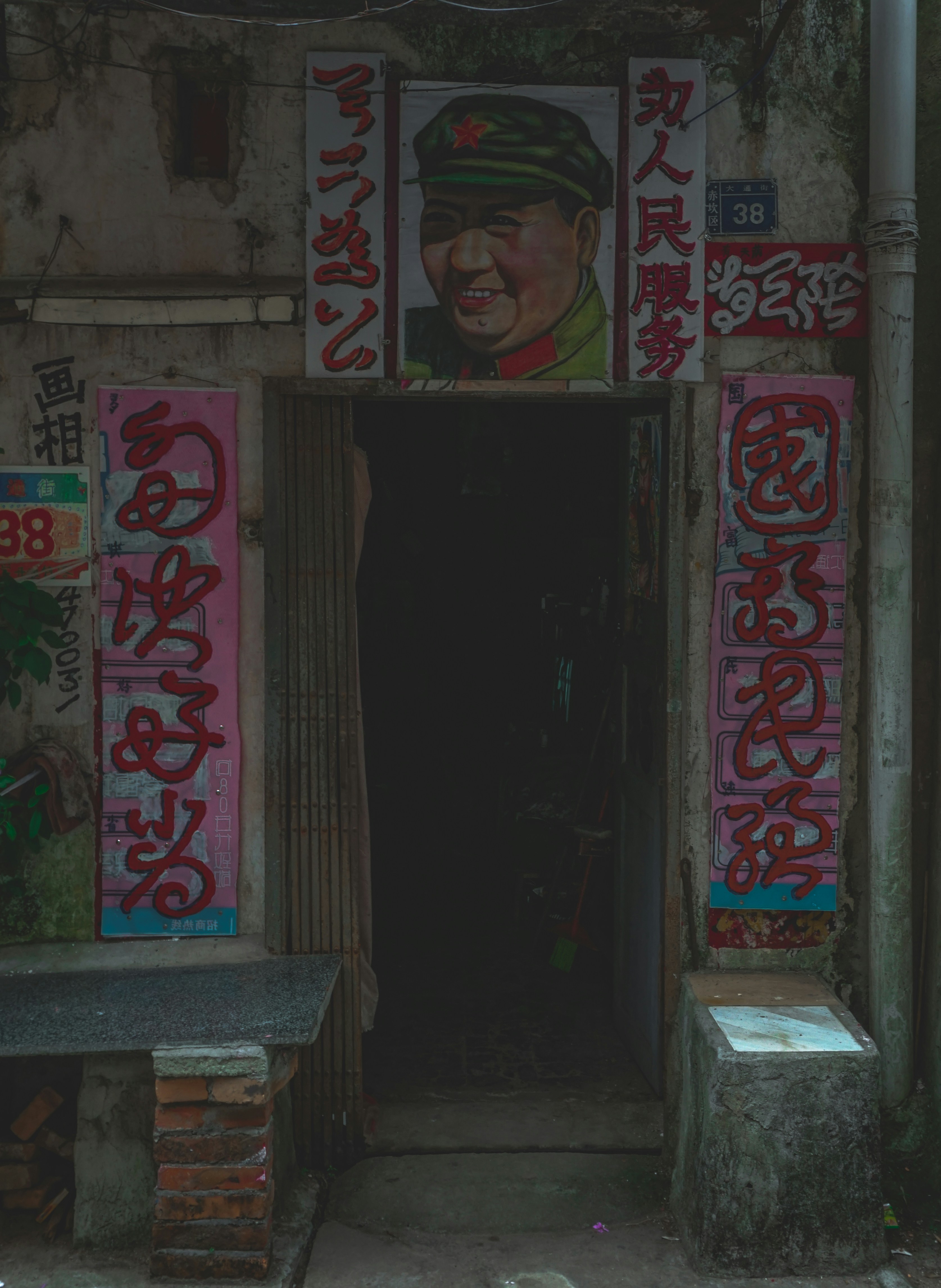 A weathered entrance adorned with vibrant propaganda posters, hinting at a bygone political landscape. The doorway invites curiosity into the shadows beyond.