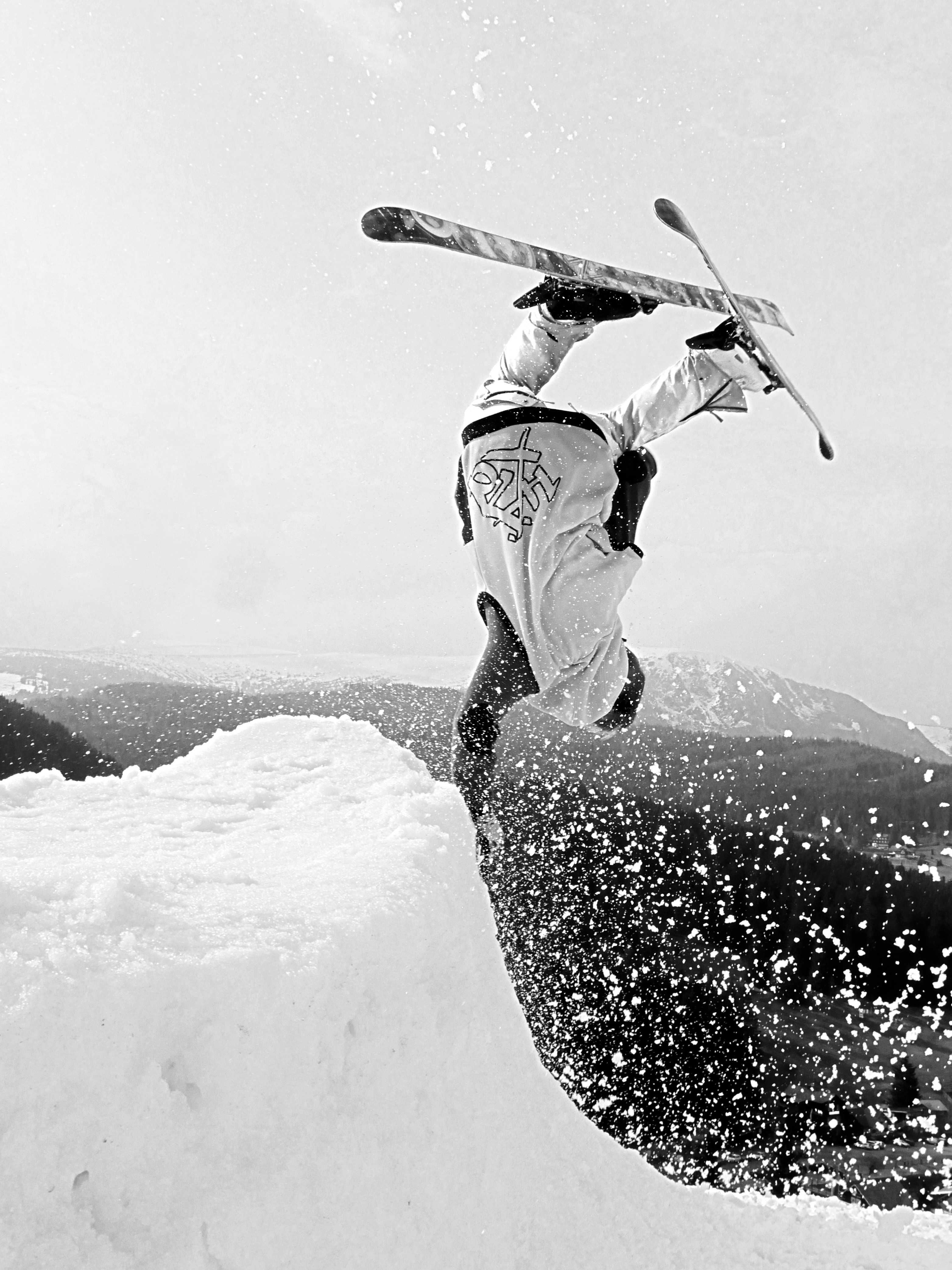 Snowboarder executing a handplant maneuver on a snowy ramp with mountains in the background.