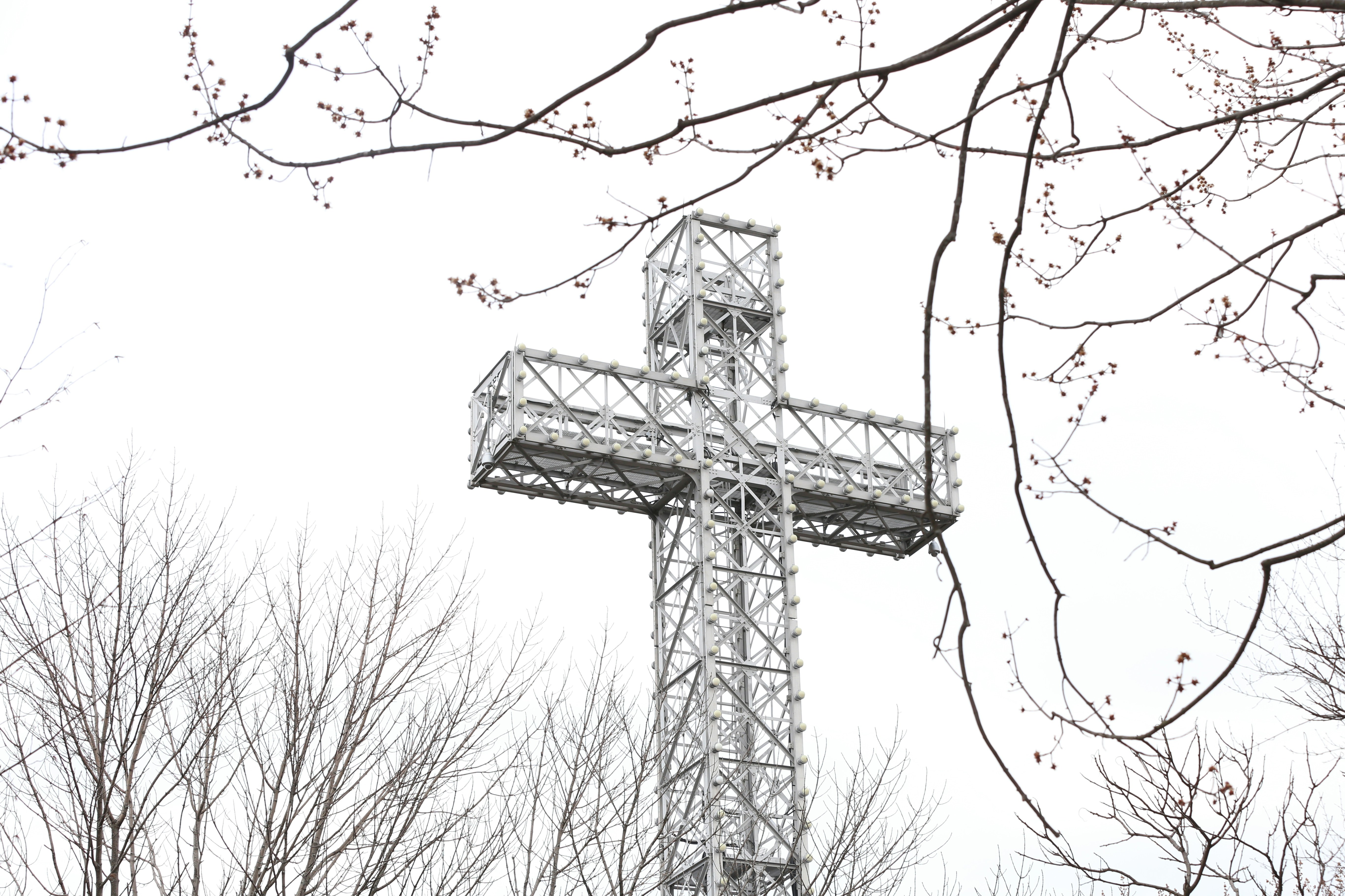 Iron Monolith: A Quiet Winter Cross Looming Over Bare Trees
