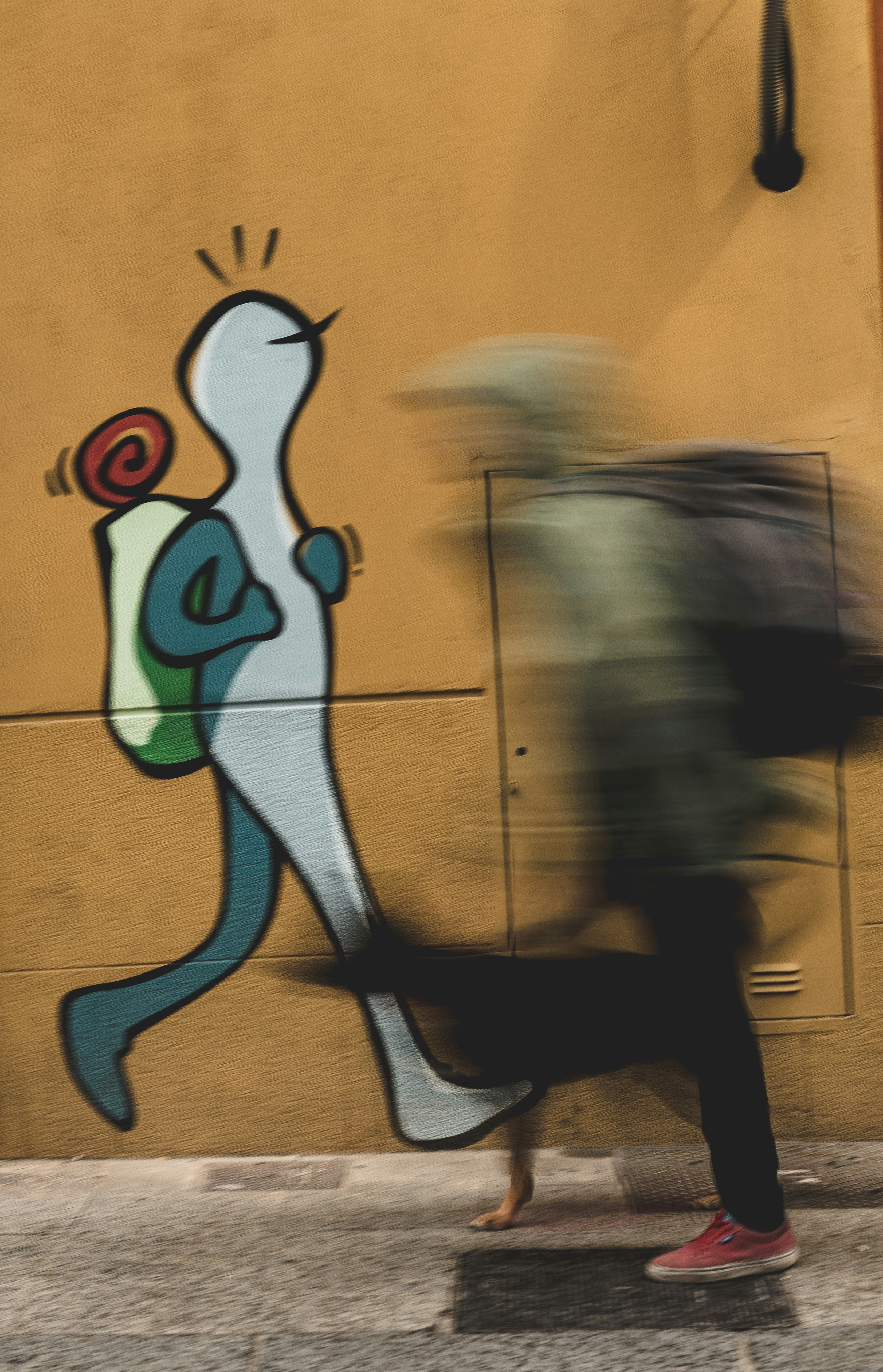 The Watchful Graffiti: A Static Figure Amid a Blurred Pedestrian