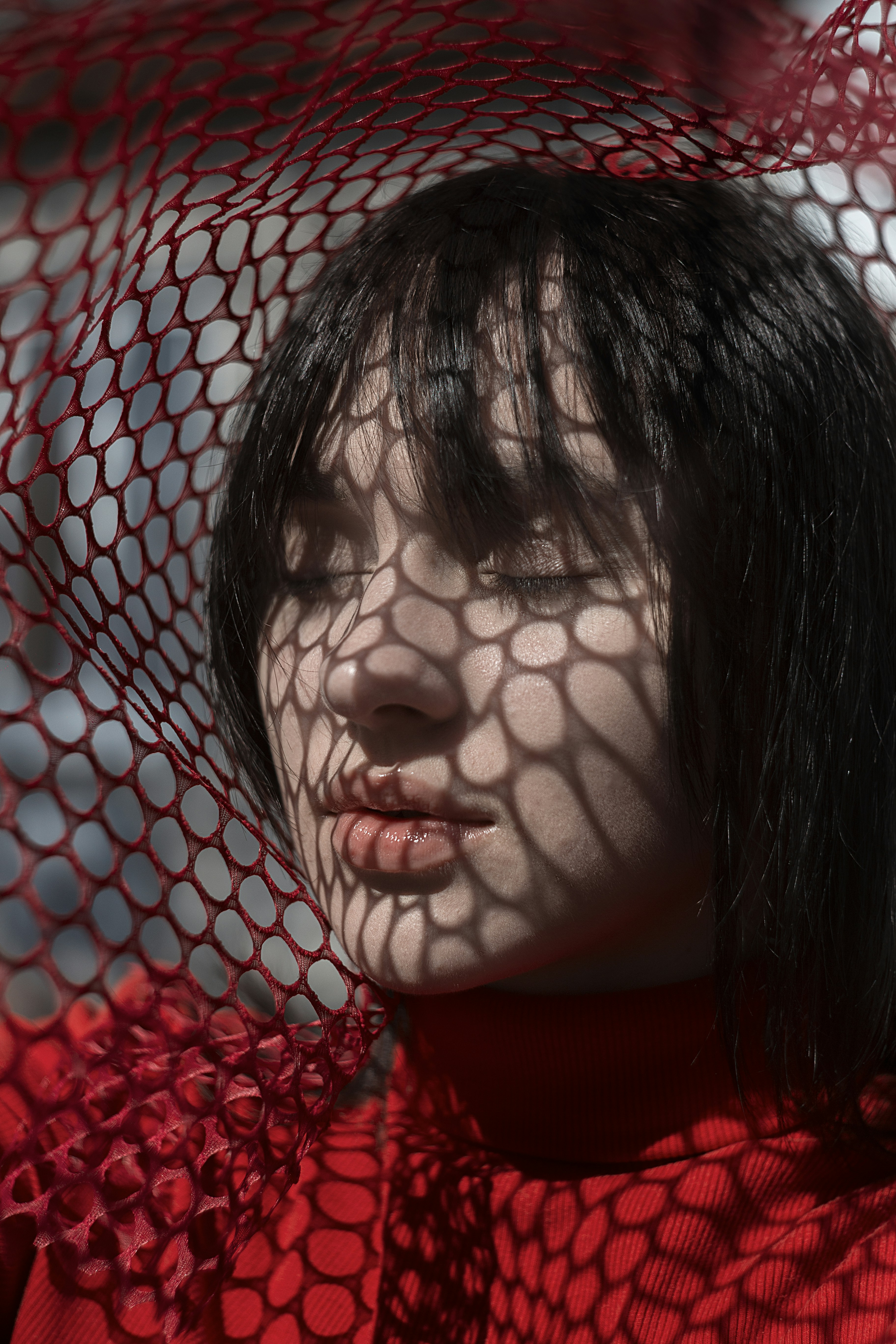 Shadowed Mesh Portrait: Quiet Mood Through a Red Veil