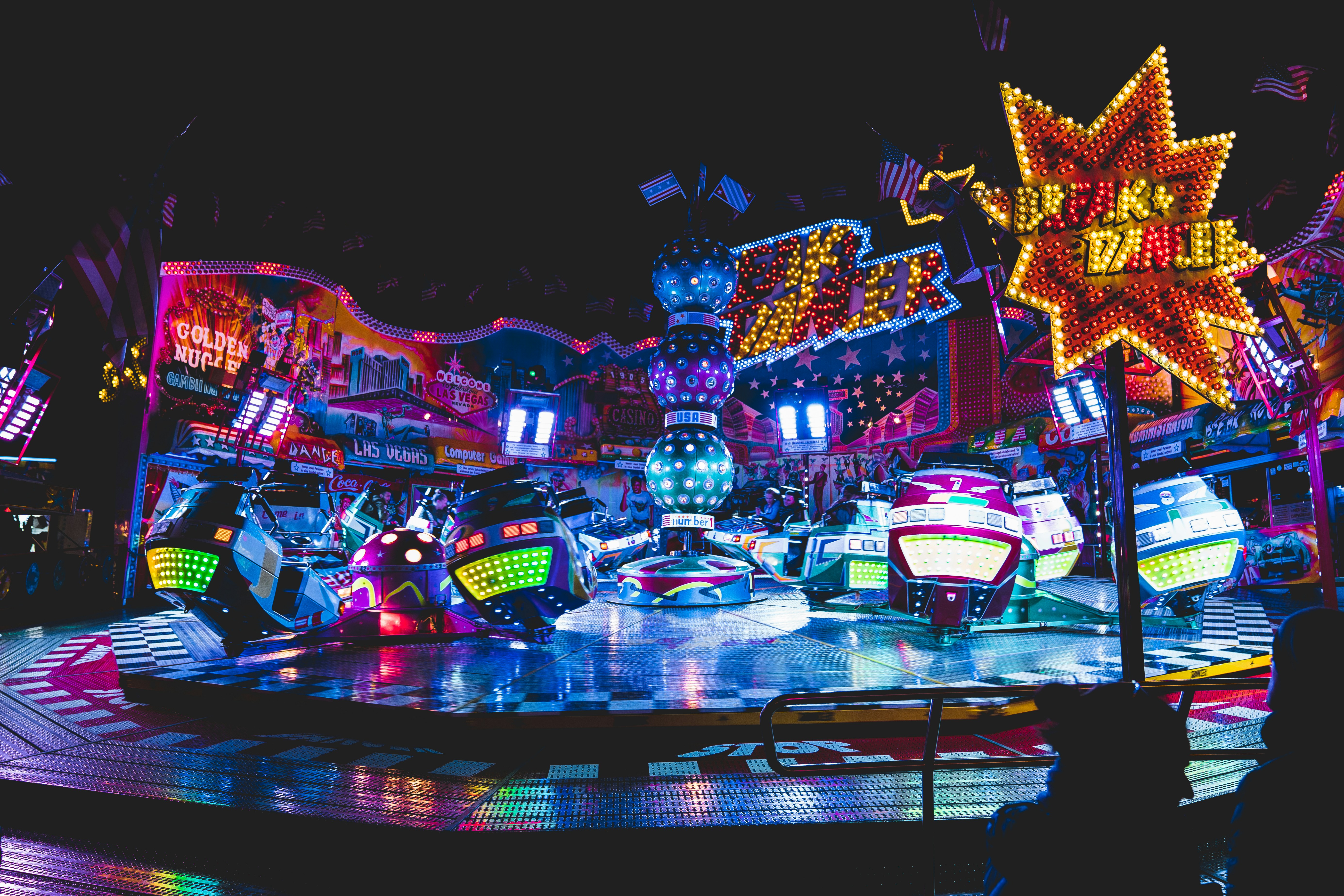 Vibrant carnival ride illuminated by colorful lights, surrounded by festive decorations and a lively atmosphere.