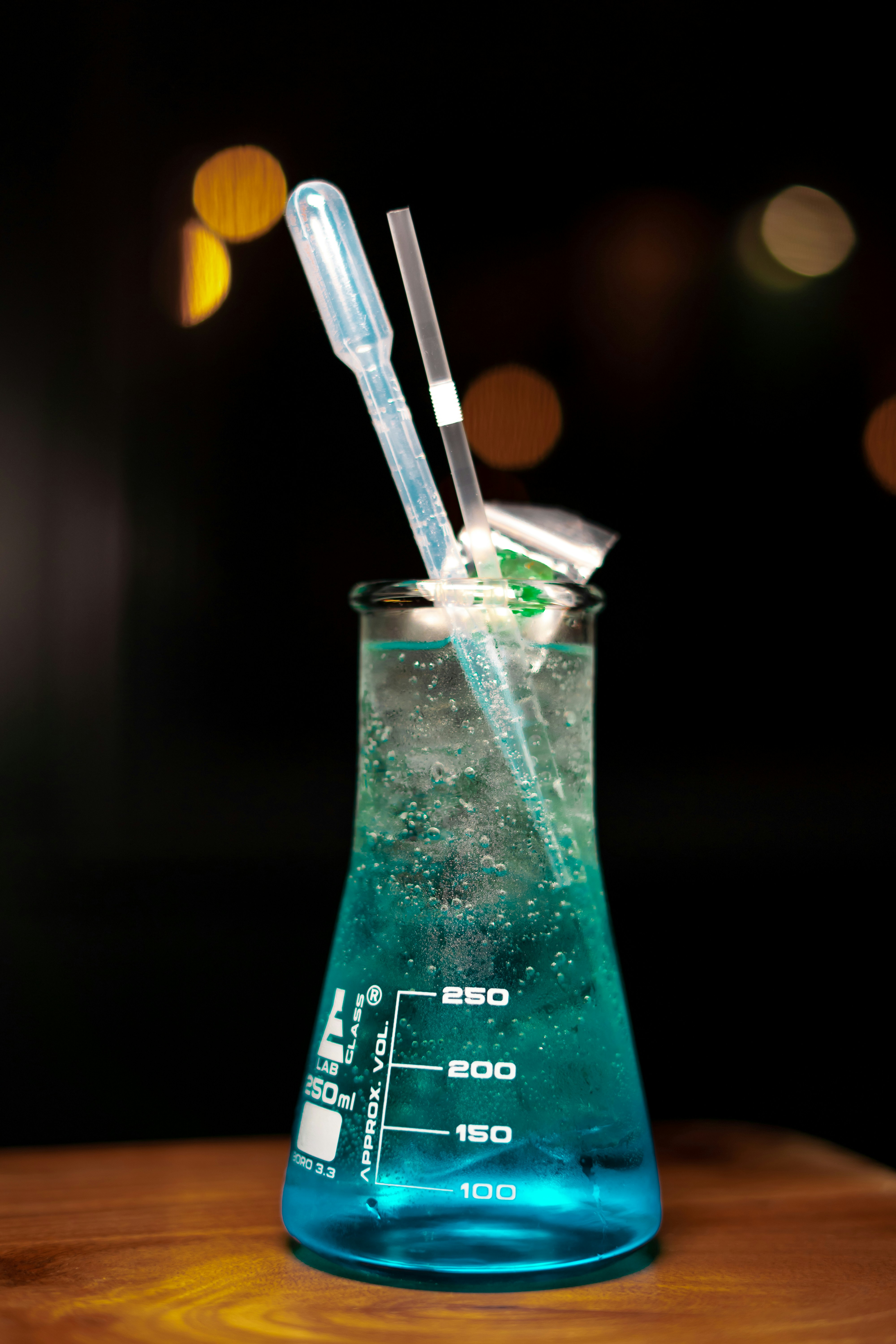 A beaker filled with vibrant blue liquid, accompanied by laboratory tools, set against a softly blurred background. The scene evokes a sense of scientific discovery.