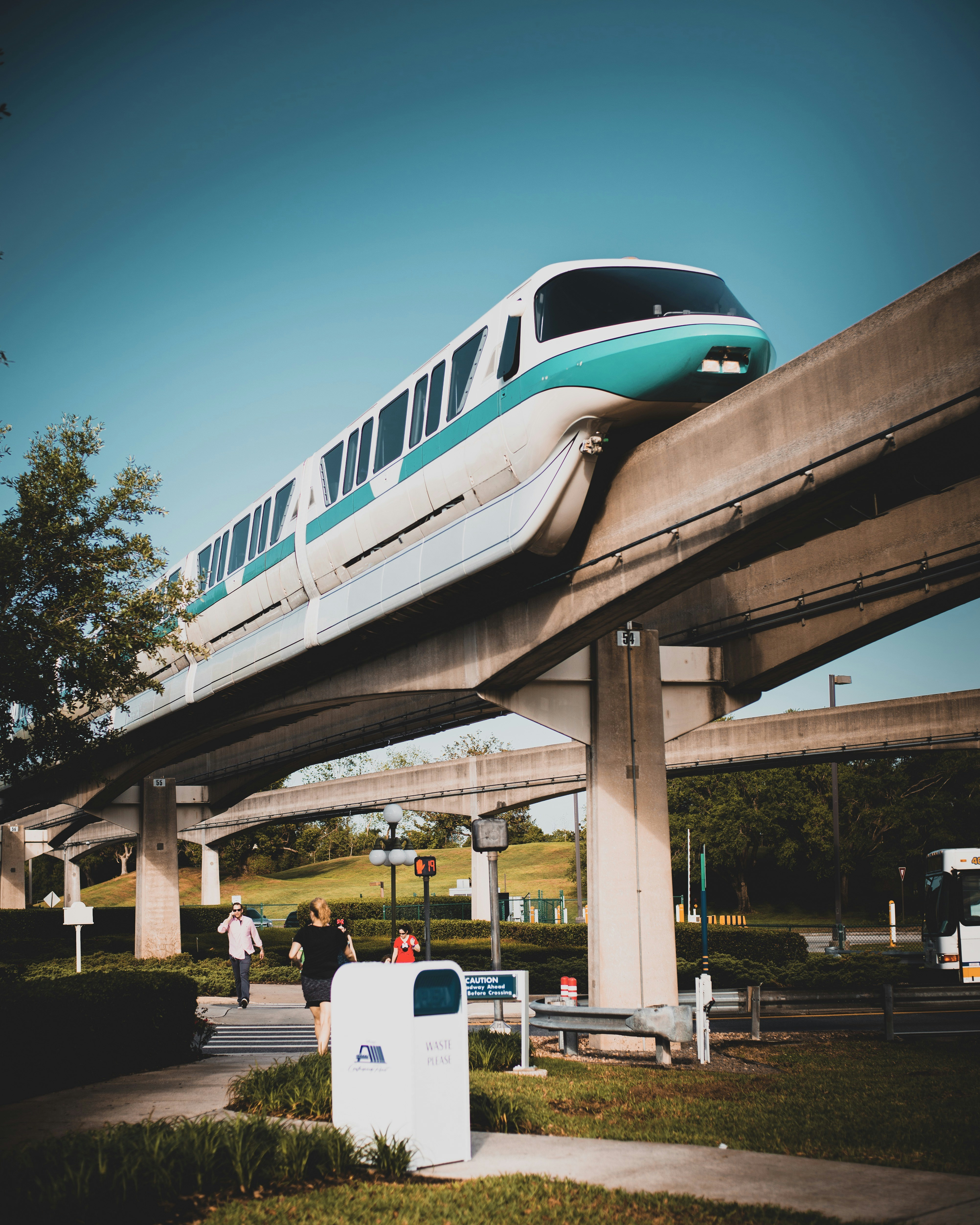 Monorail gliding smoothly along its tracks, surrounded by lush greenery and pedestrians. The scene captures the blend of modern transport and nature.