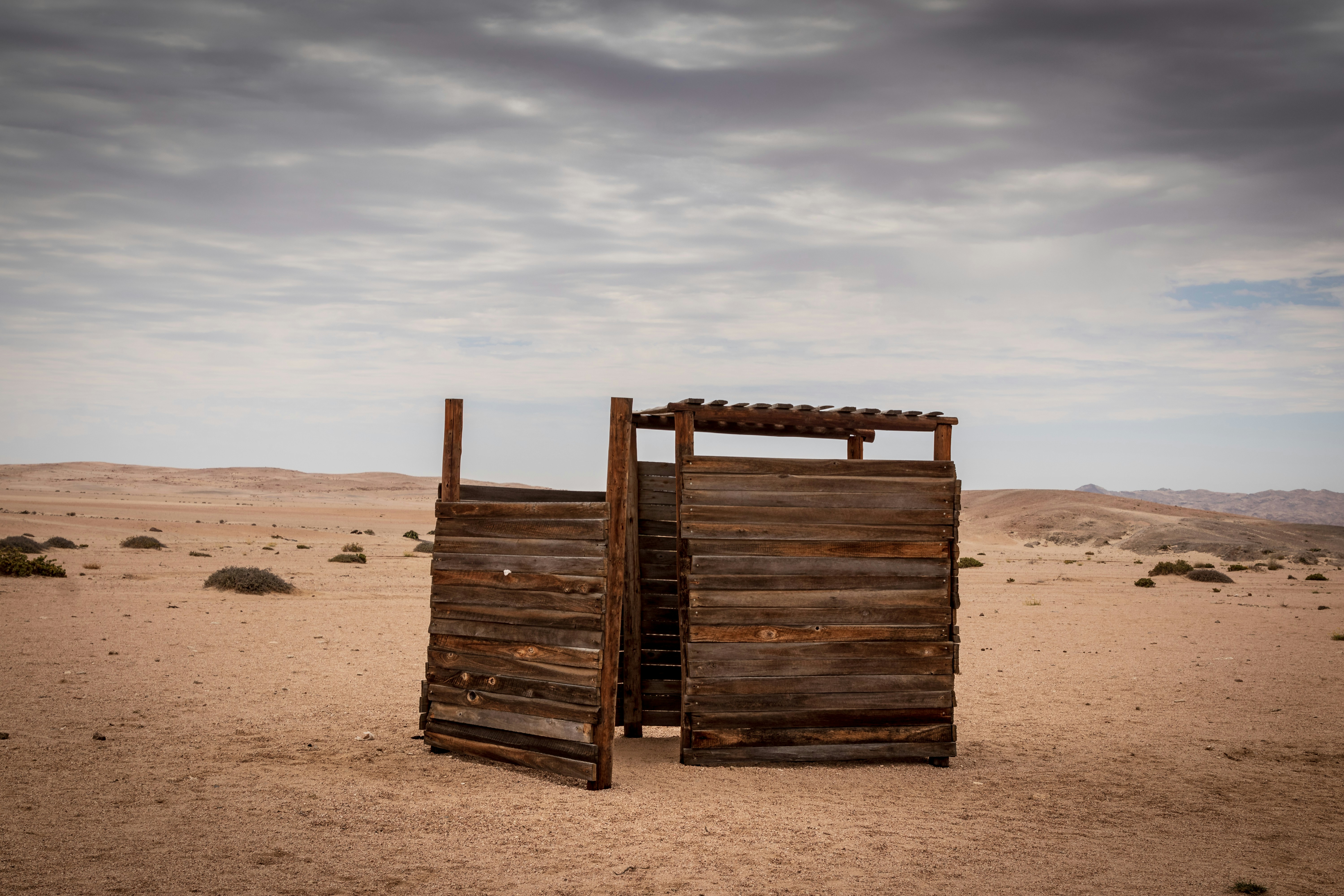 Desert Gatehouse: Weathered Planks Rising in a Quiet Dune Landscape